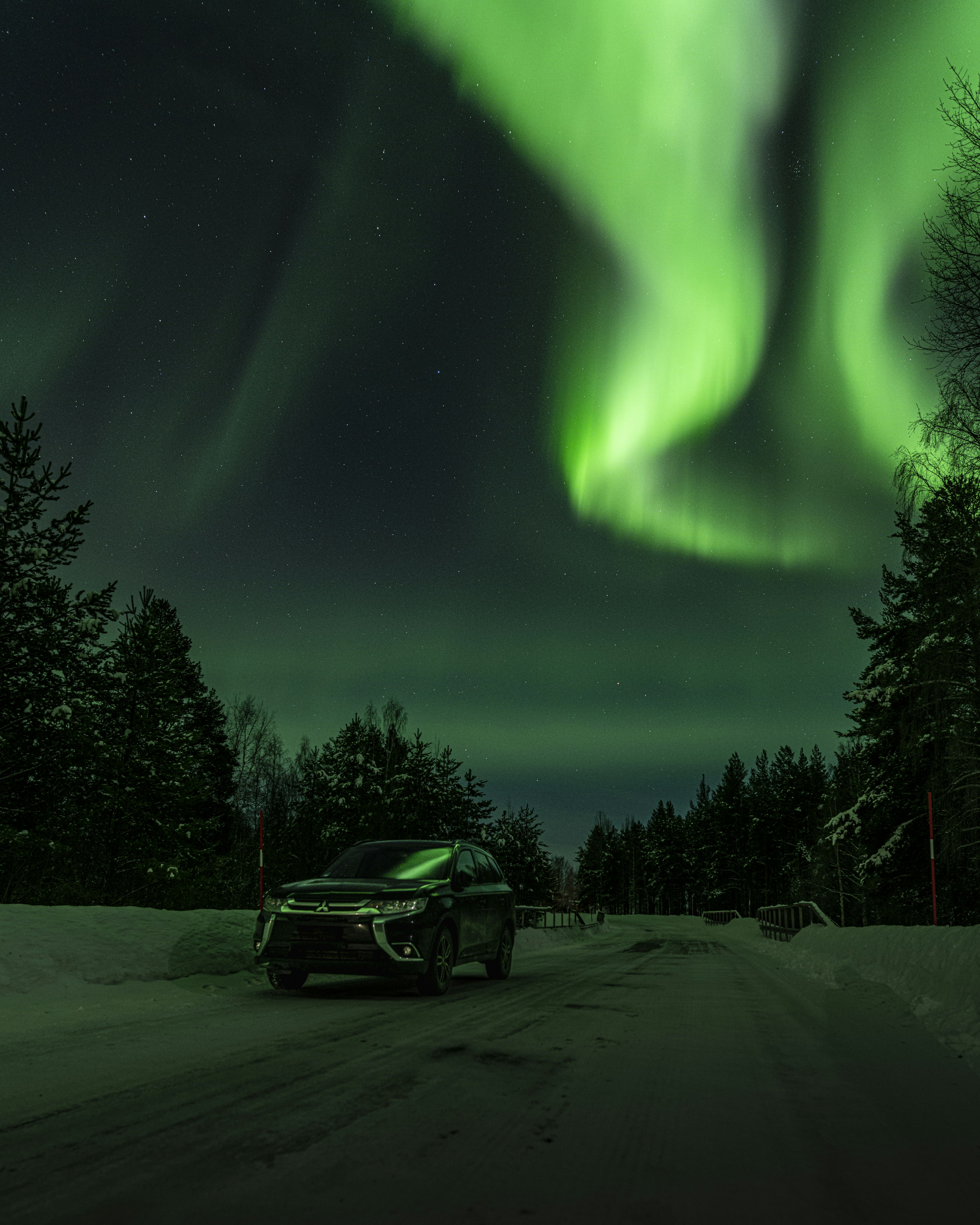 A car driving down a snow covered road under a green light photo – Free ...