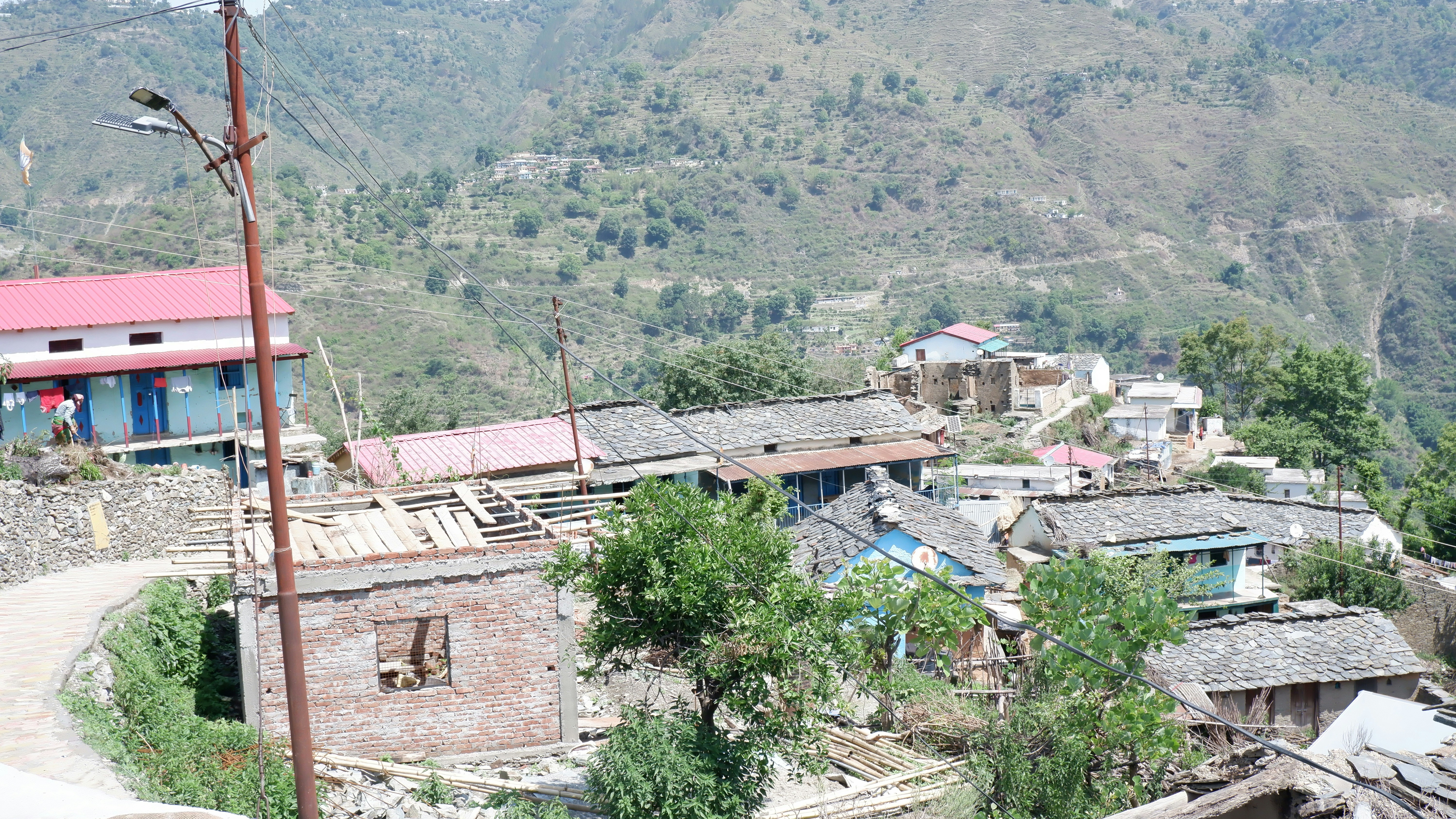 Scenic view of hillside village showcasing traditional architecture and ongoing construction amidst lush greenery.