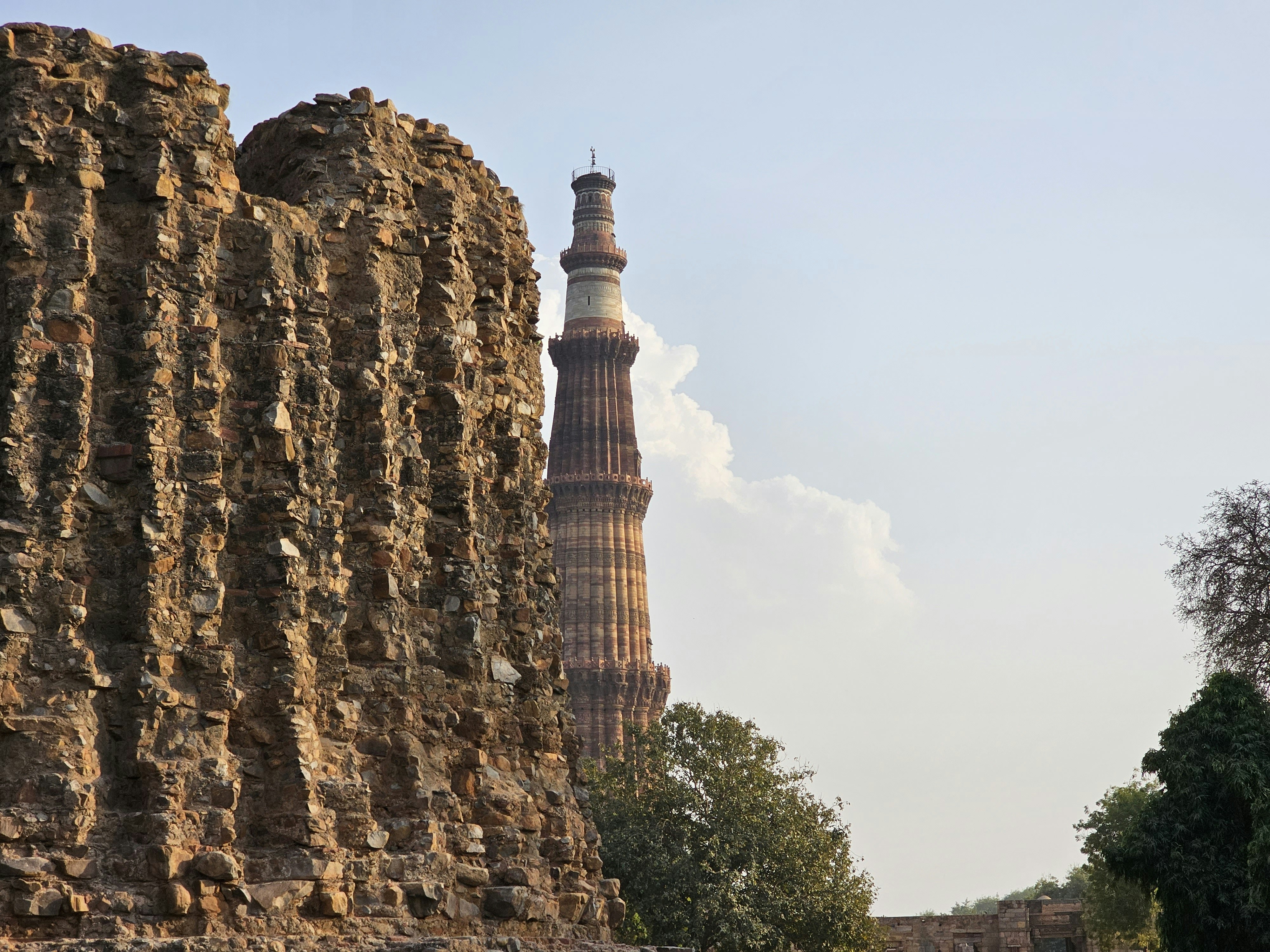 Weathered Walls Frame the Qutub Minar Against a Clear Afternoon Sky
