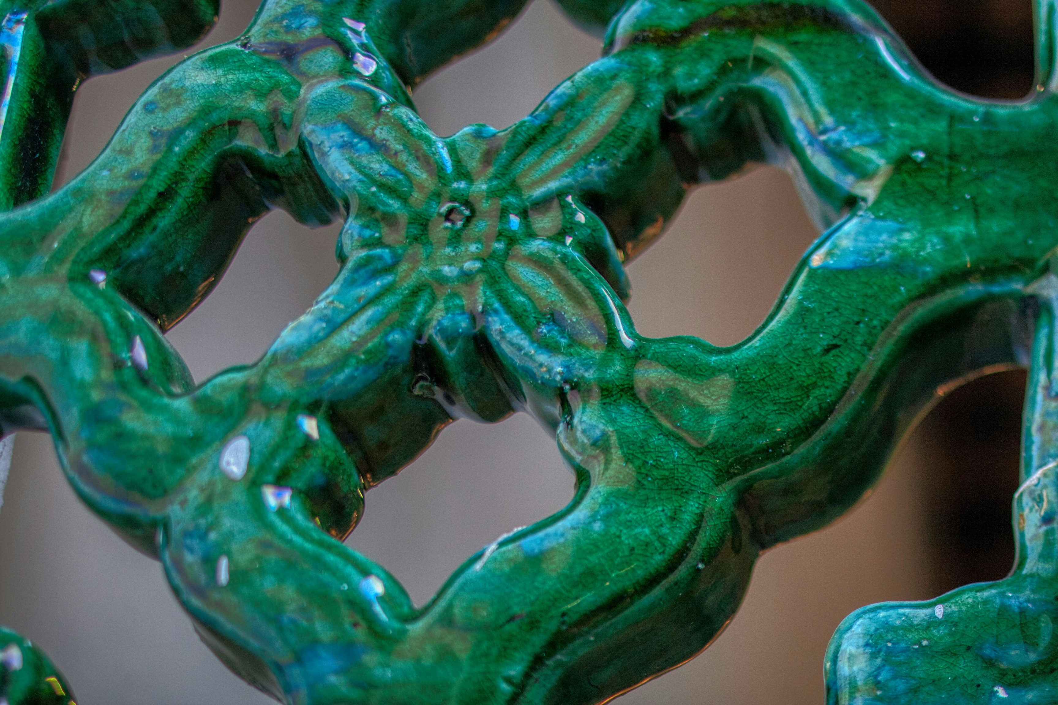 Close-up of a beautifully crafted green ceramic tile with intricate patterns and a glossy finish.