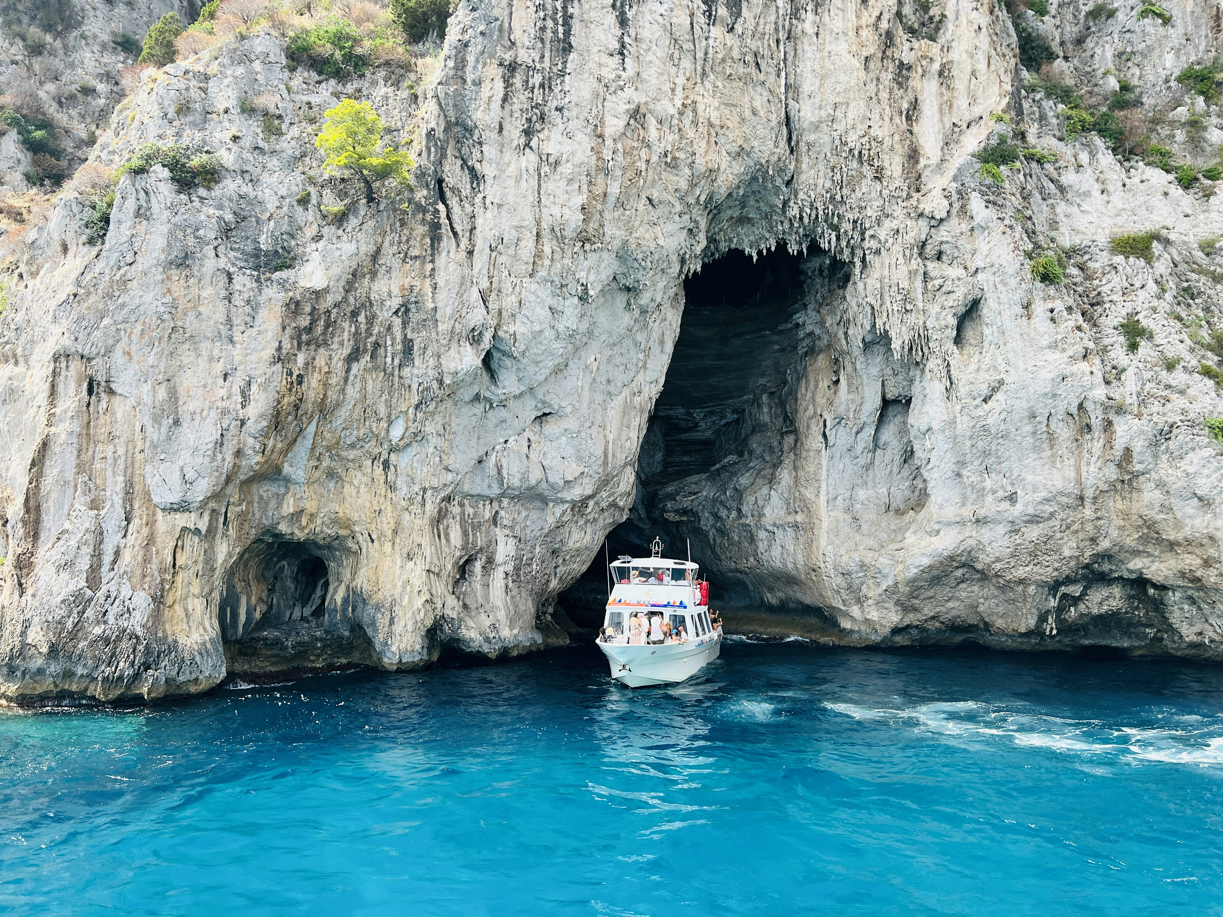 A boat in the water near a large rock formation photo – Free Capri ...