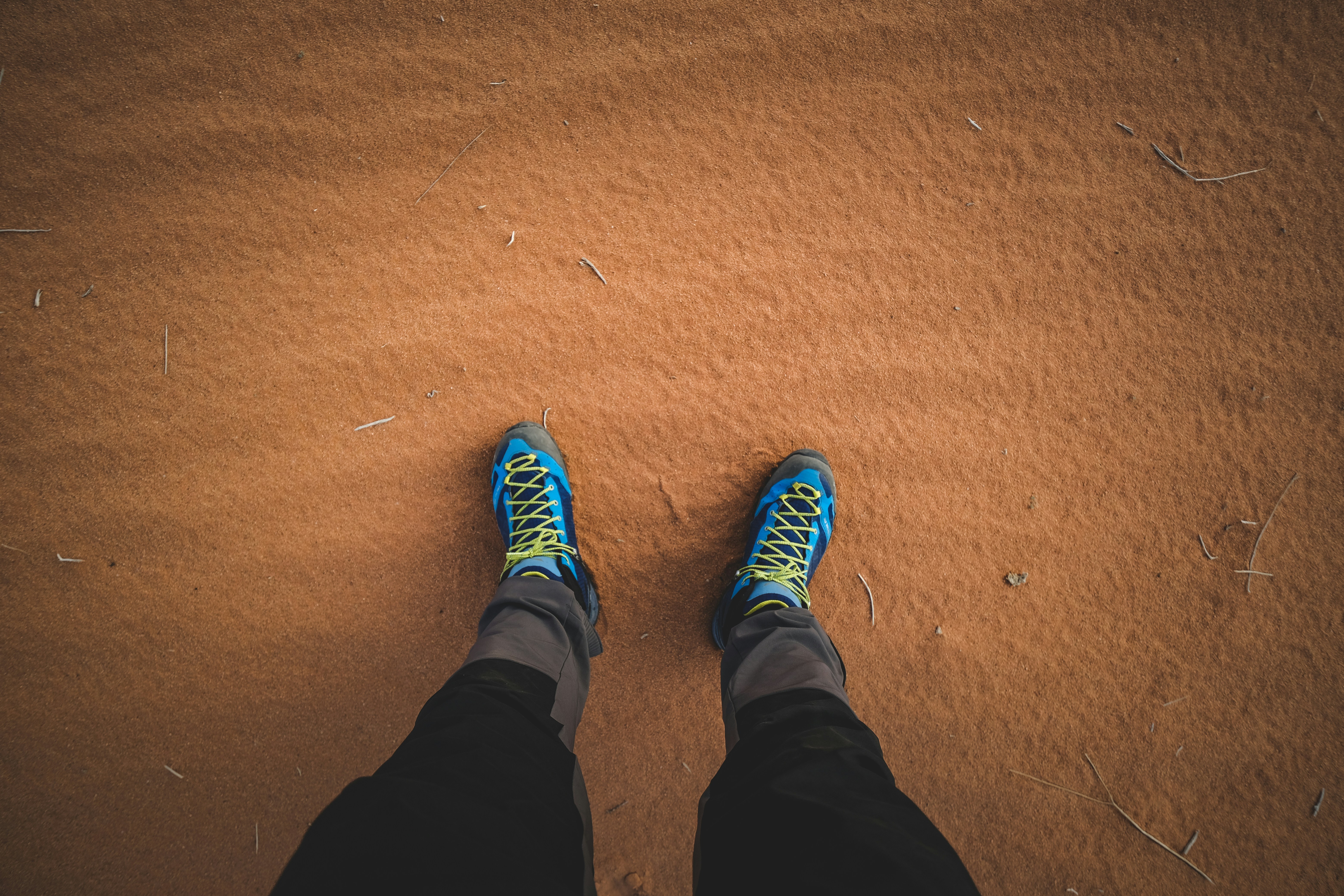 a person with blue shoes standing in the sand