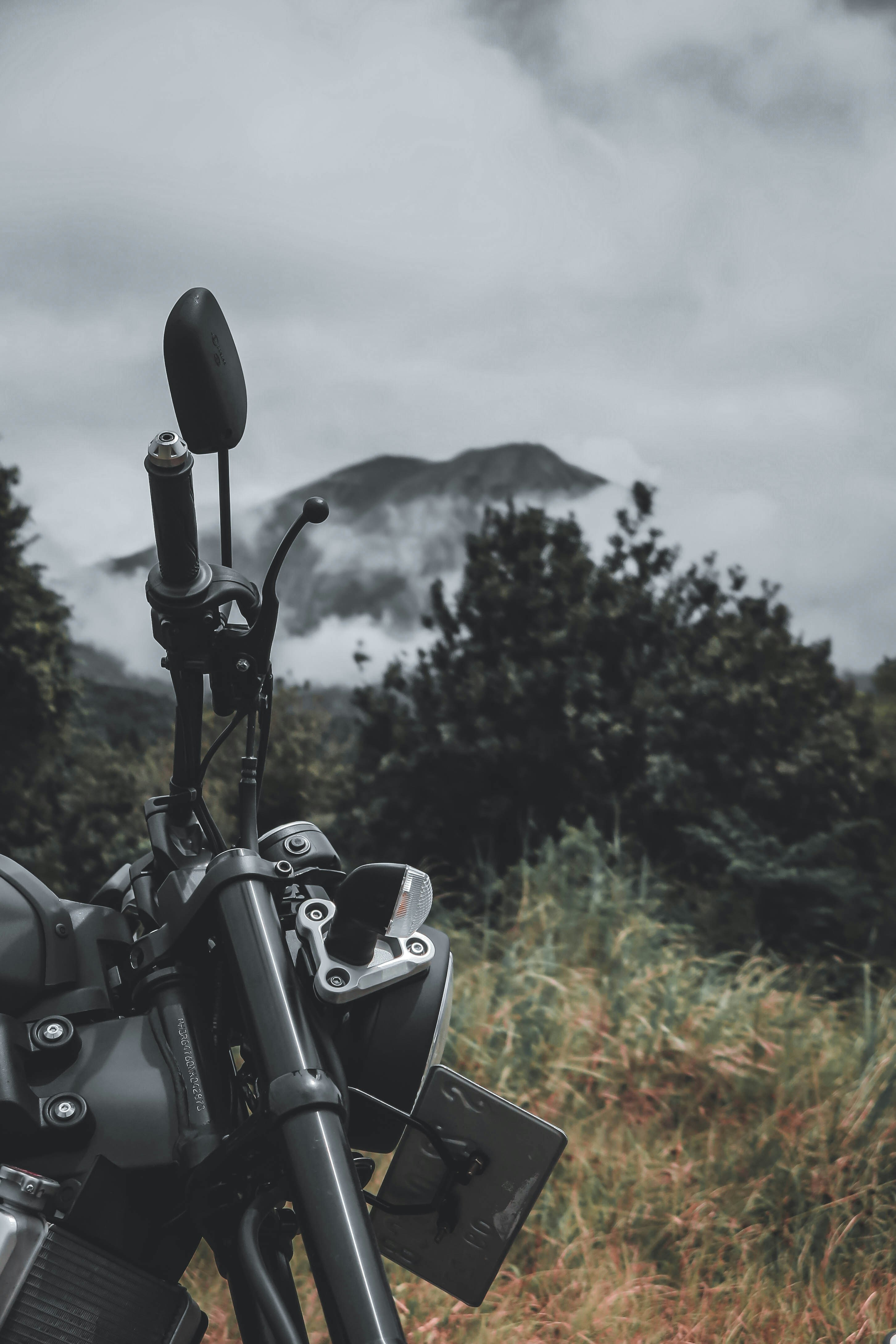 Close-up of a rugged motorcycle handlebar against a misty mountain landscape