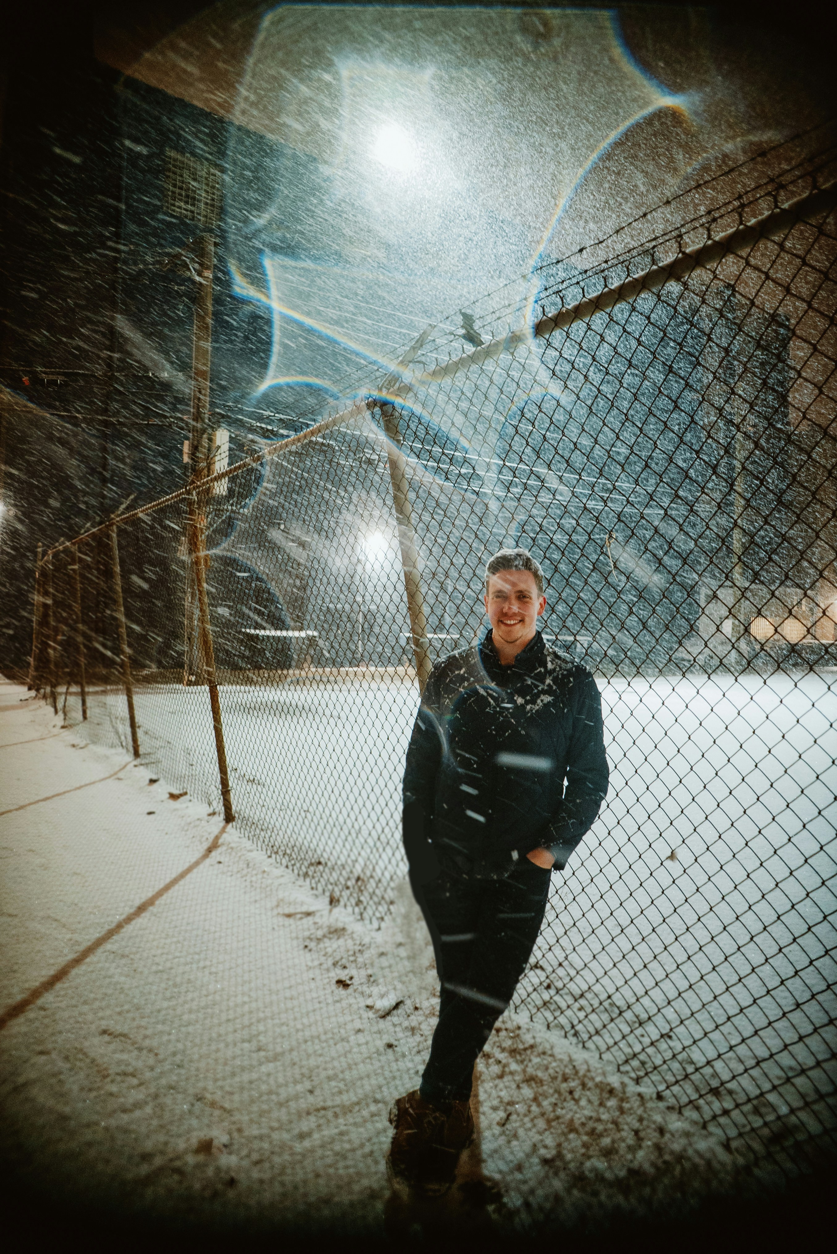 a man standing in front of a fence in the snow