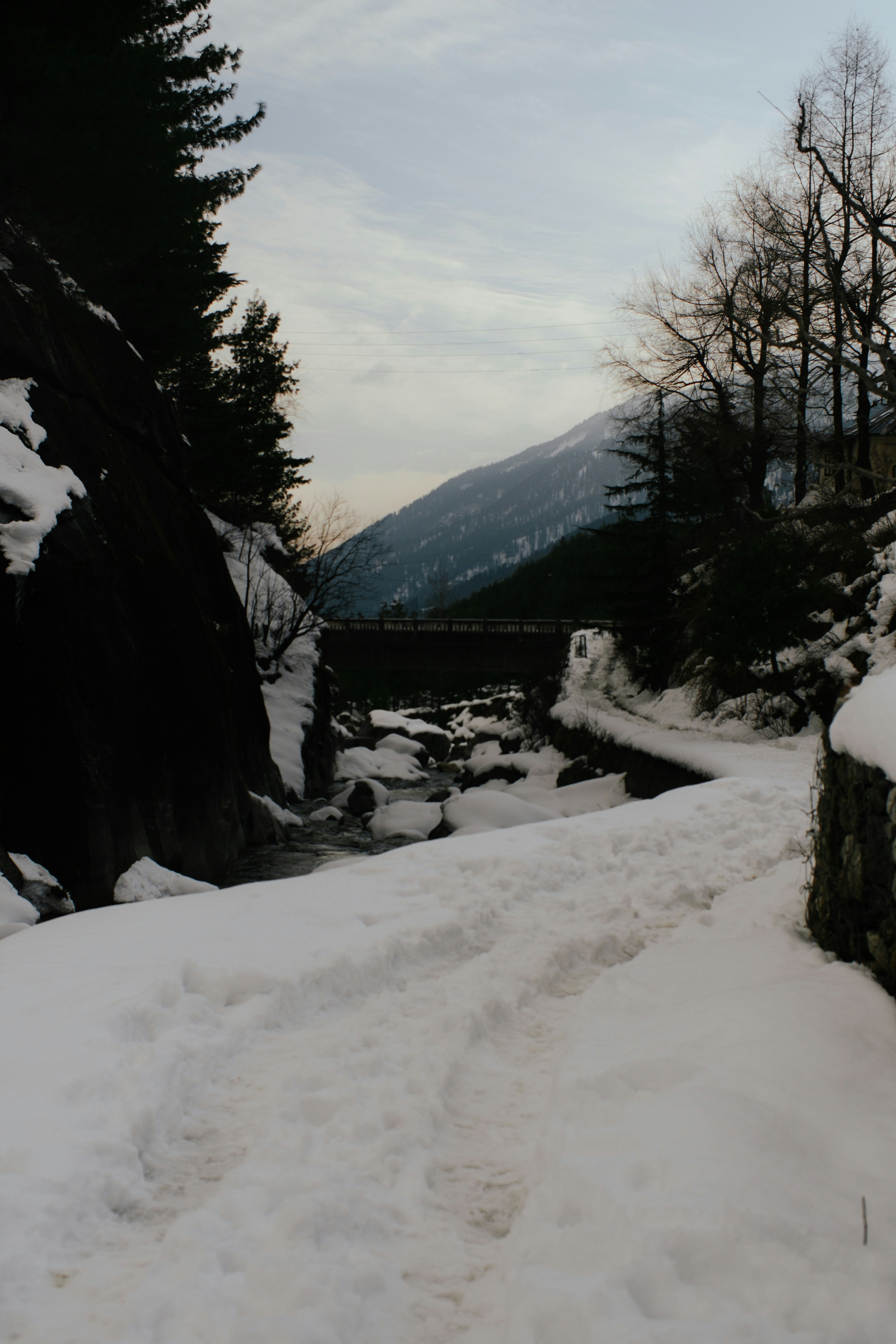 Snowbound Gorge Bridge: Distant Peaks Loom Over a Quiet Winter Path