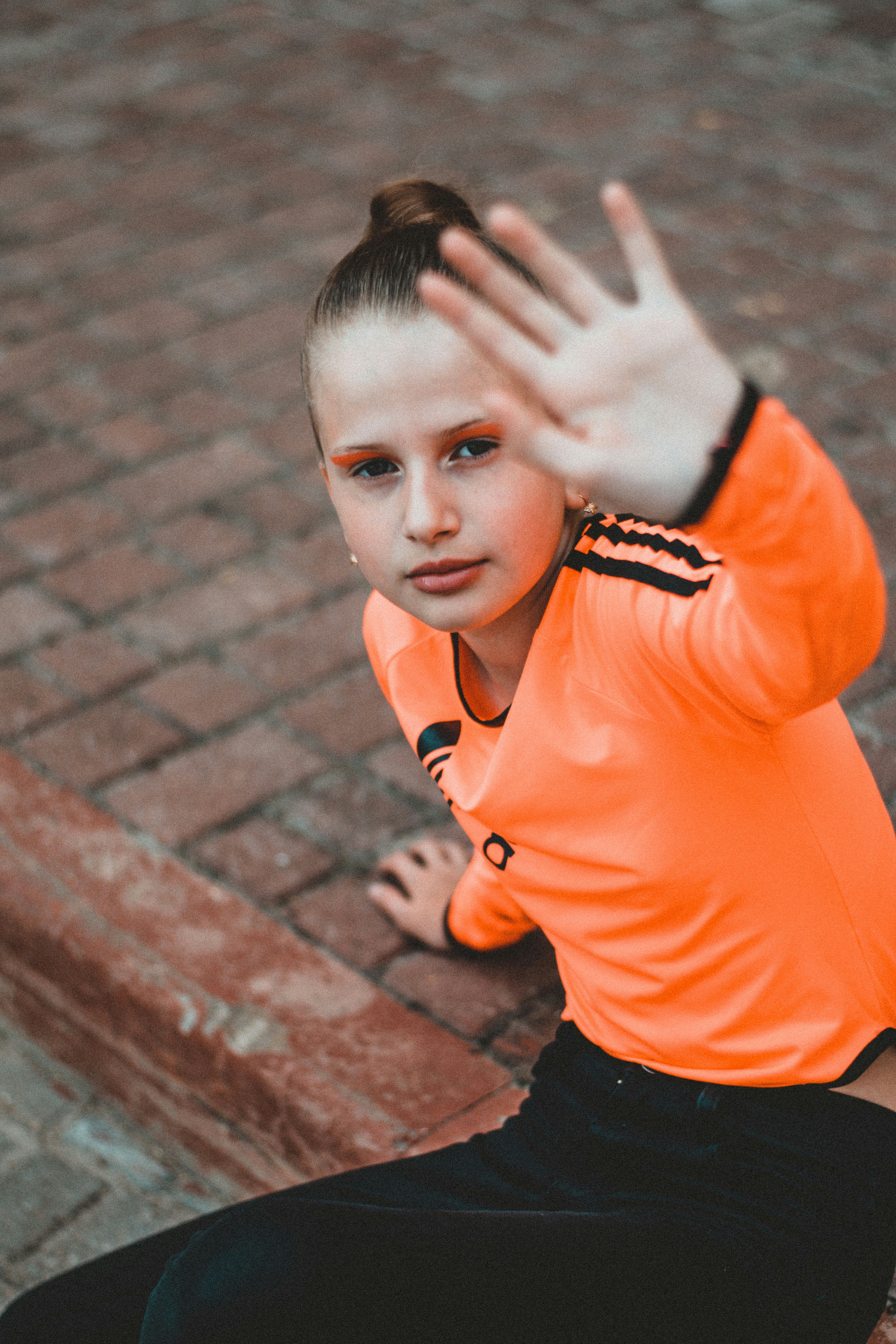 a young girl sitting on the ground with her hand in the air