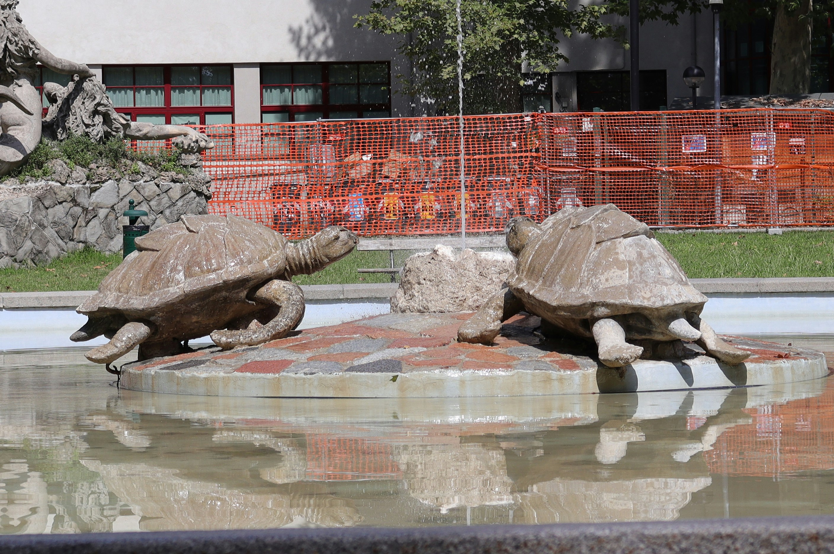 Twin Stone Tortoise Statues Guard a Circular Fountain Amid Construction Mesh