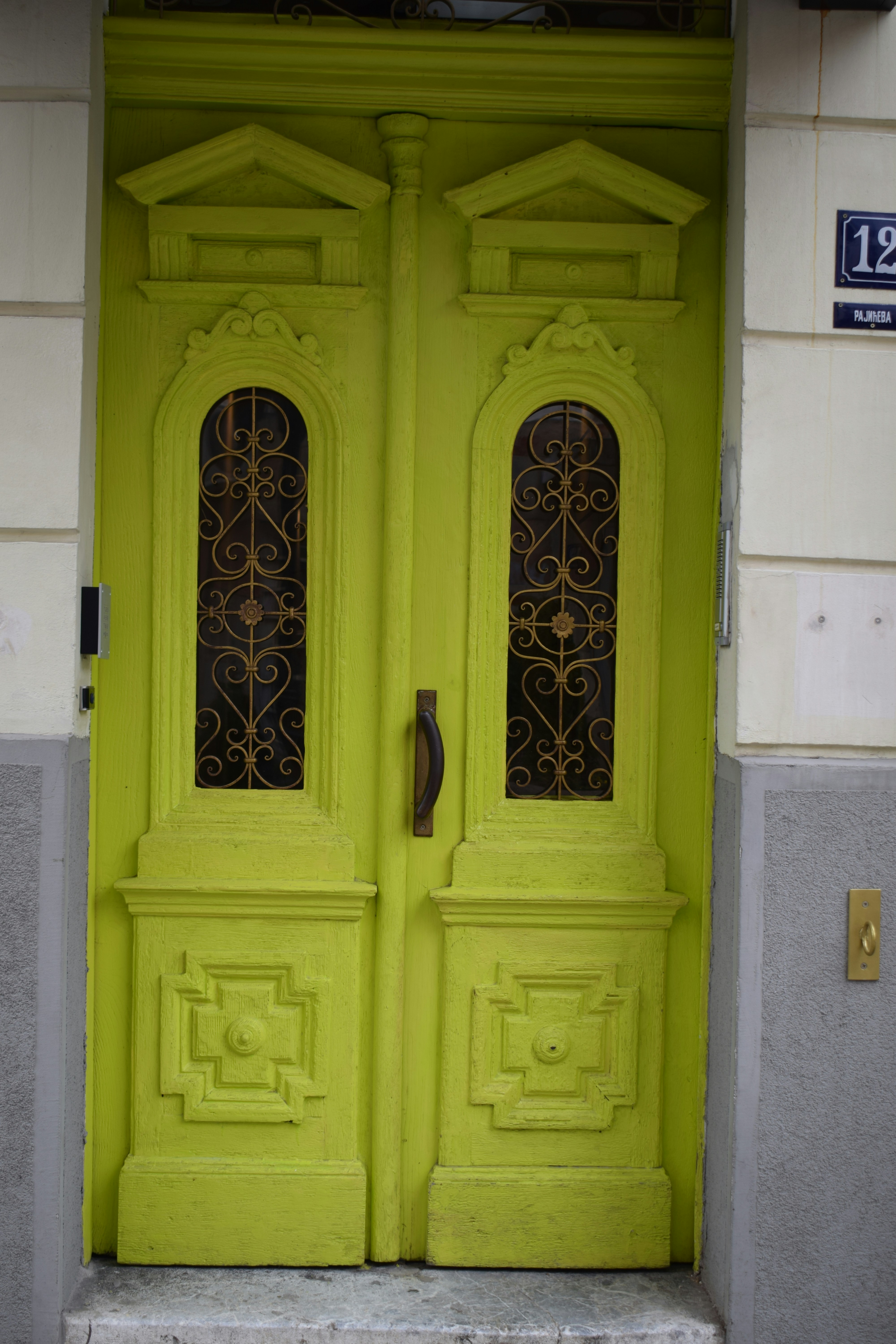 Lime-Green Threshold: Dual Doors with Intricate Ironwork