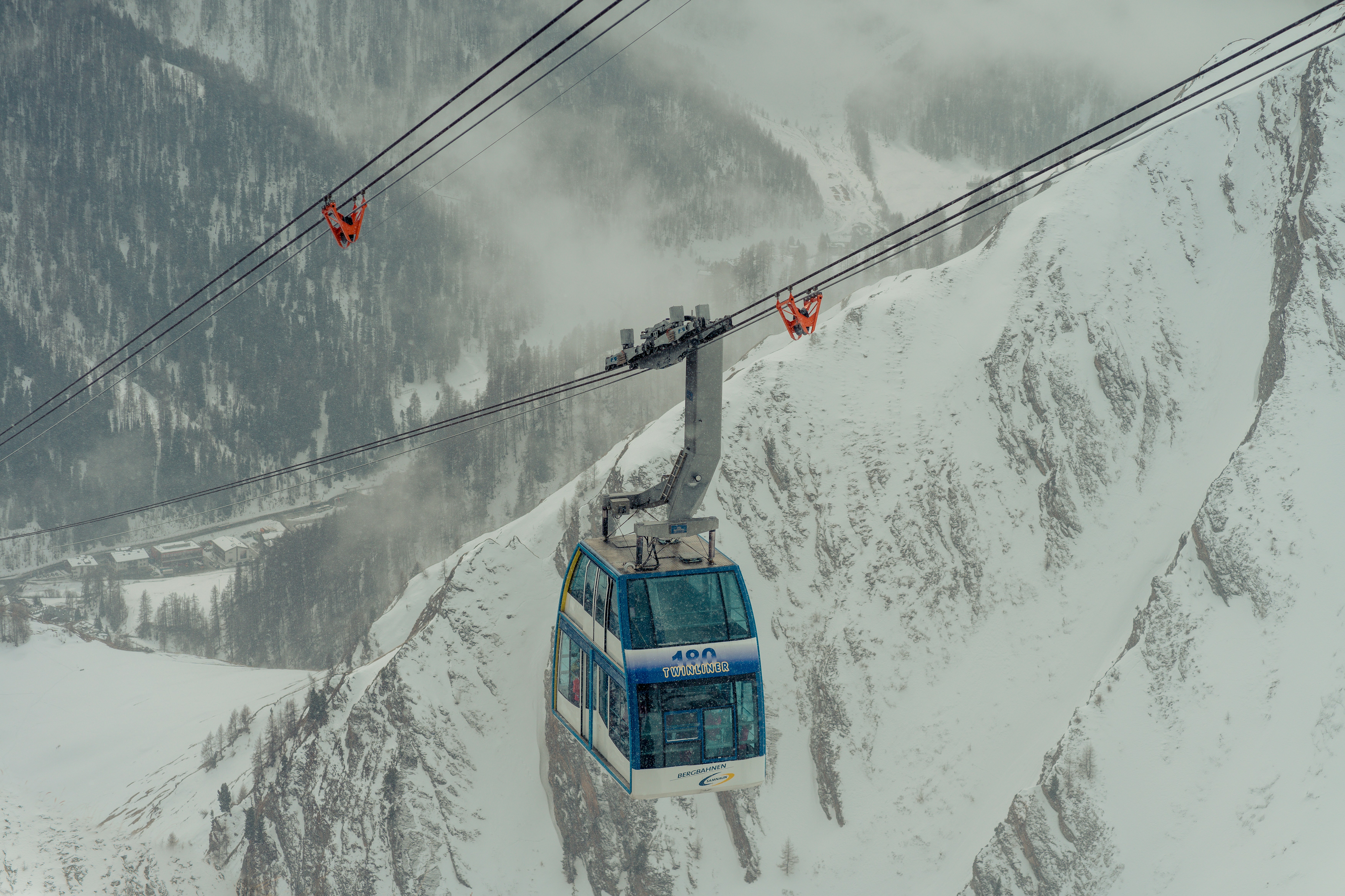Blue Cable Car Cutting Through a Snowbound Alpine Veil