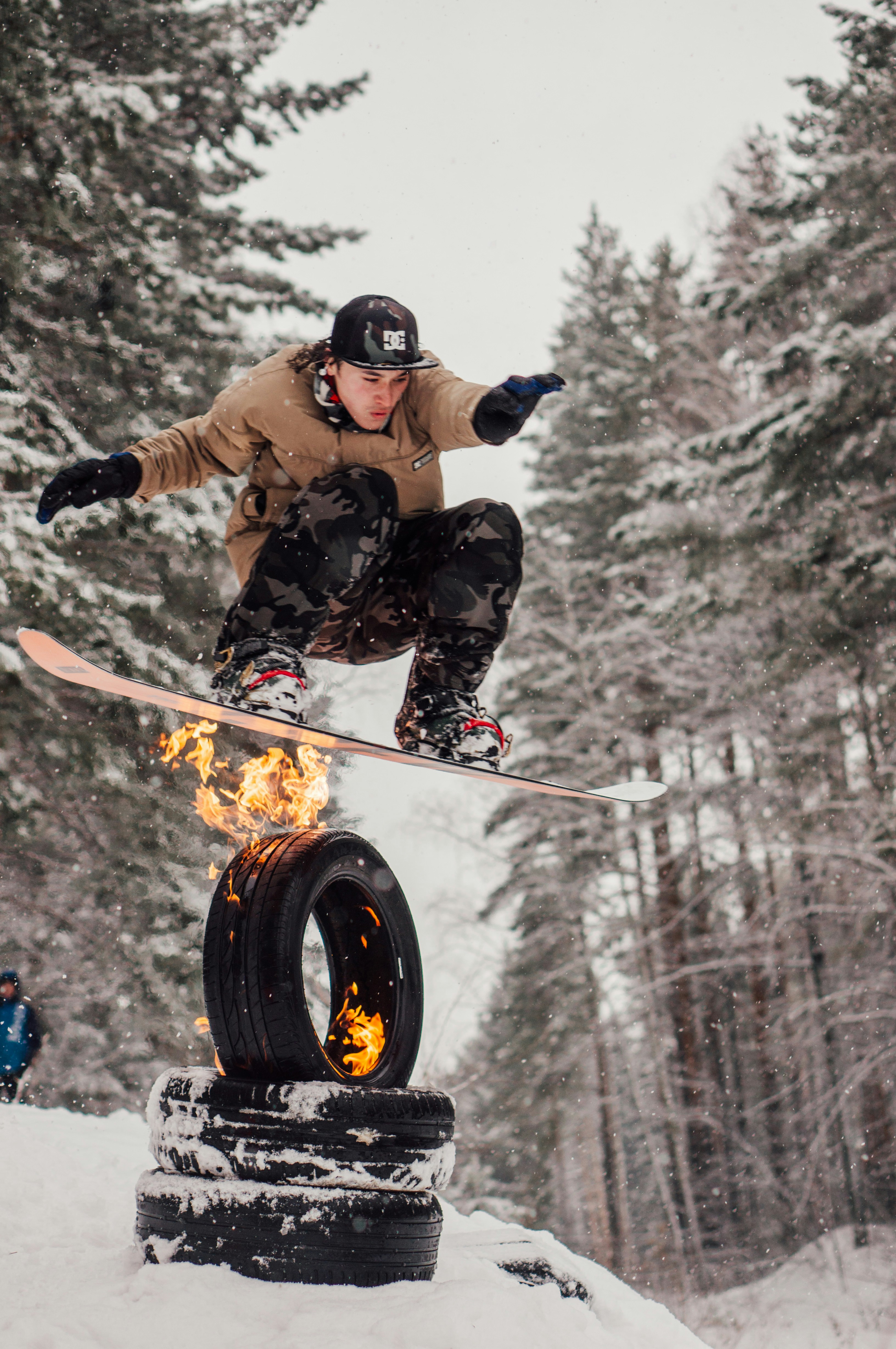 Snowbound Kickflip: Rider Launches Across a Flaming Tire Jump