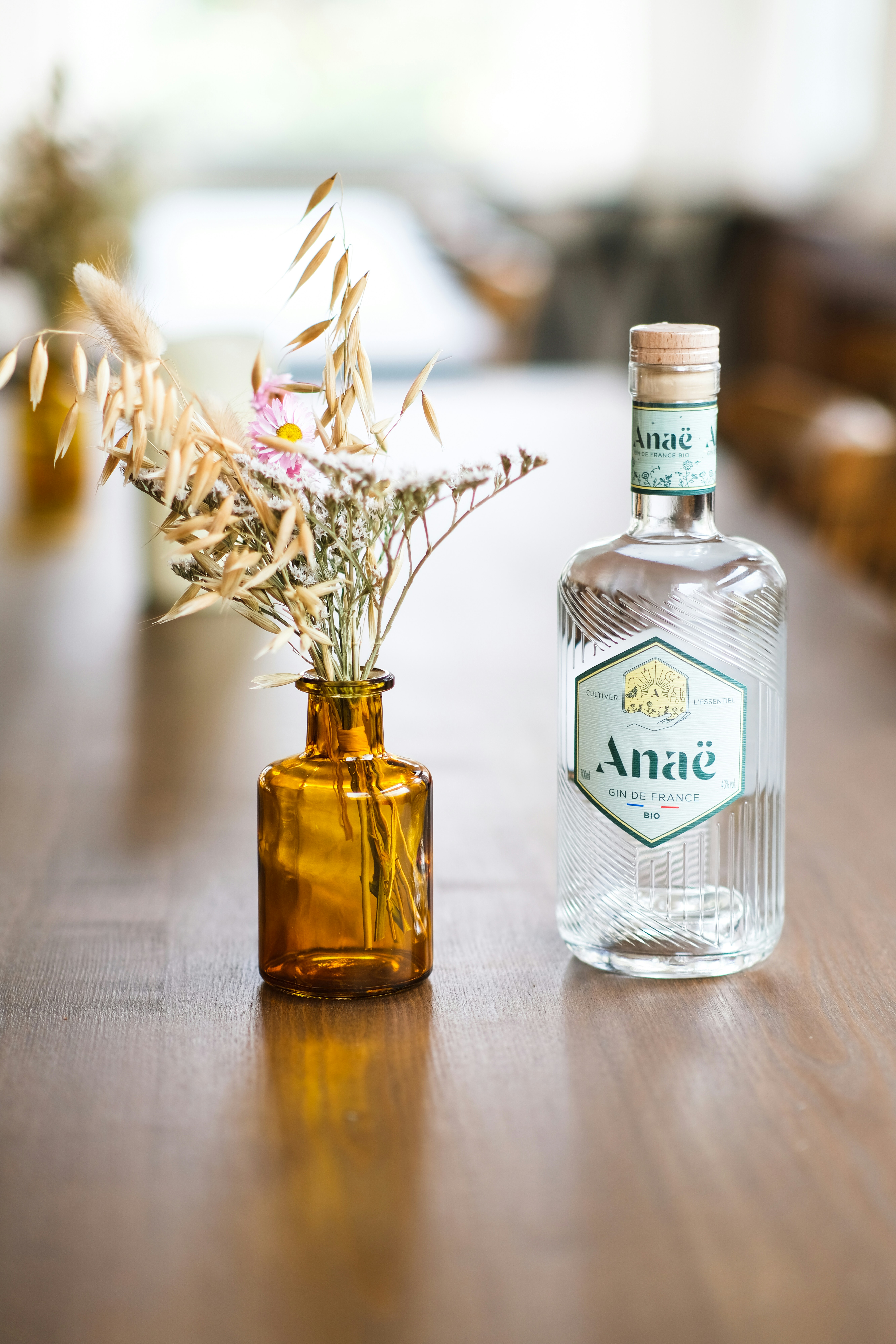 a bottle of alcohol sitting on a table next to a vase with flowers