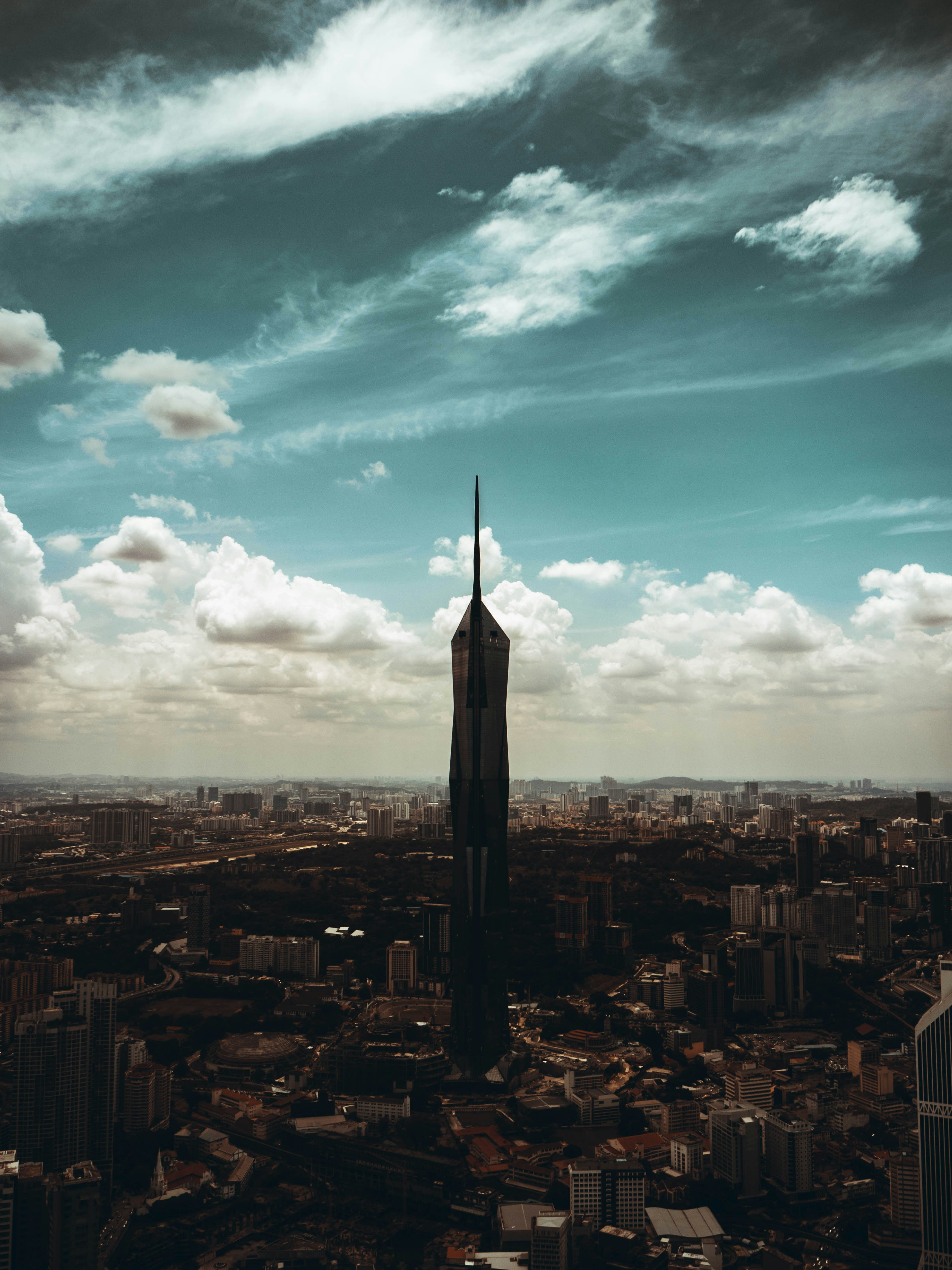 A very tall building towering over a city under a cloudy sky photo ...