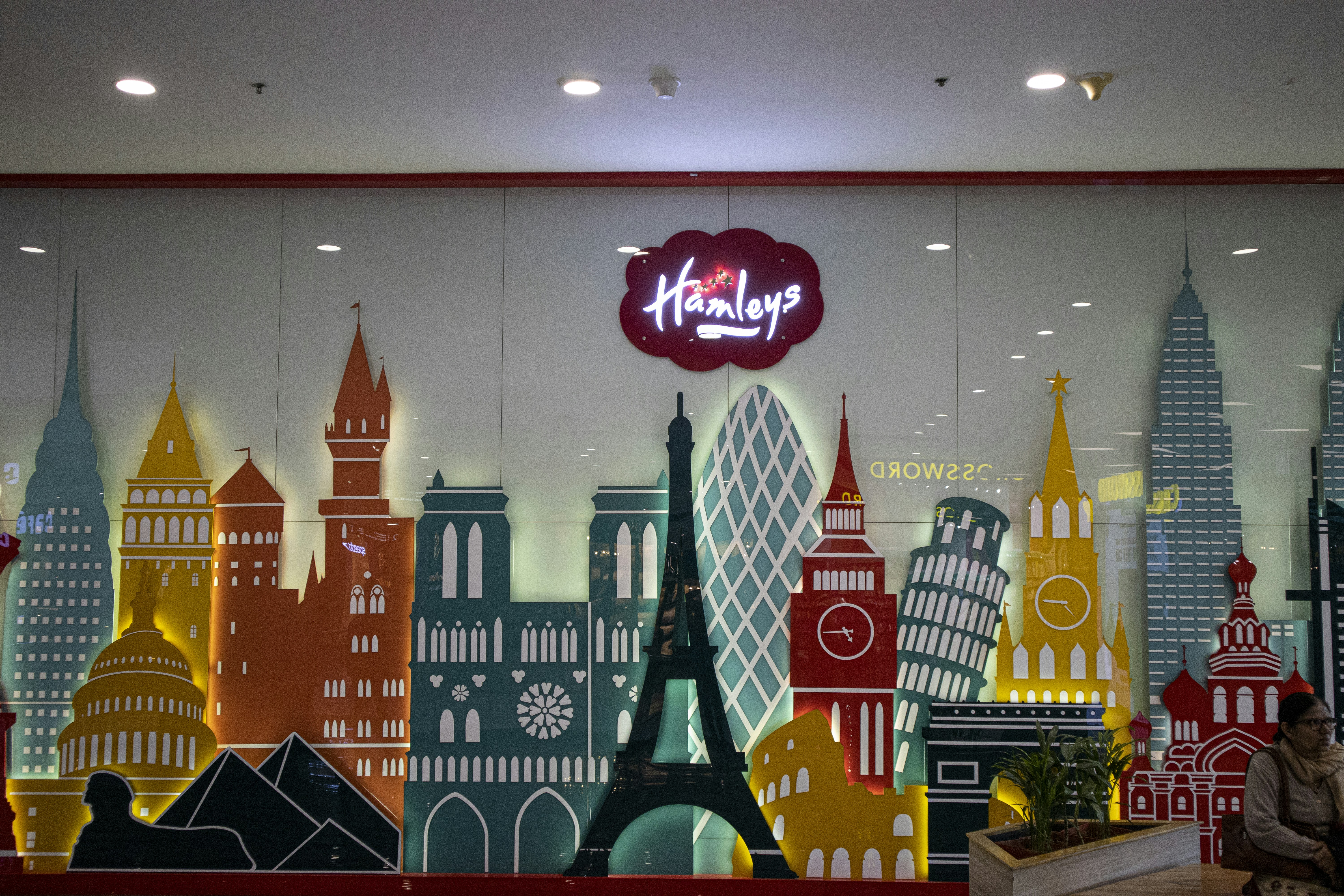 Colorful mural of iconic world landmarks with a prominent logo overhead.