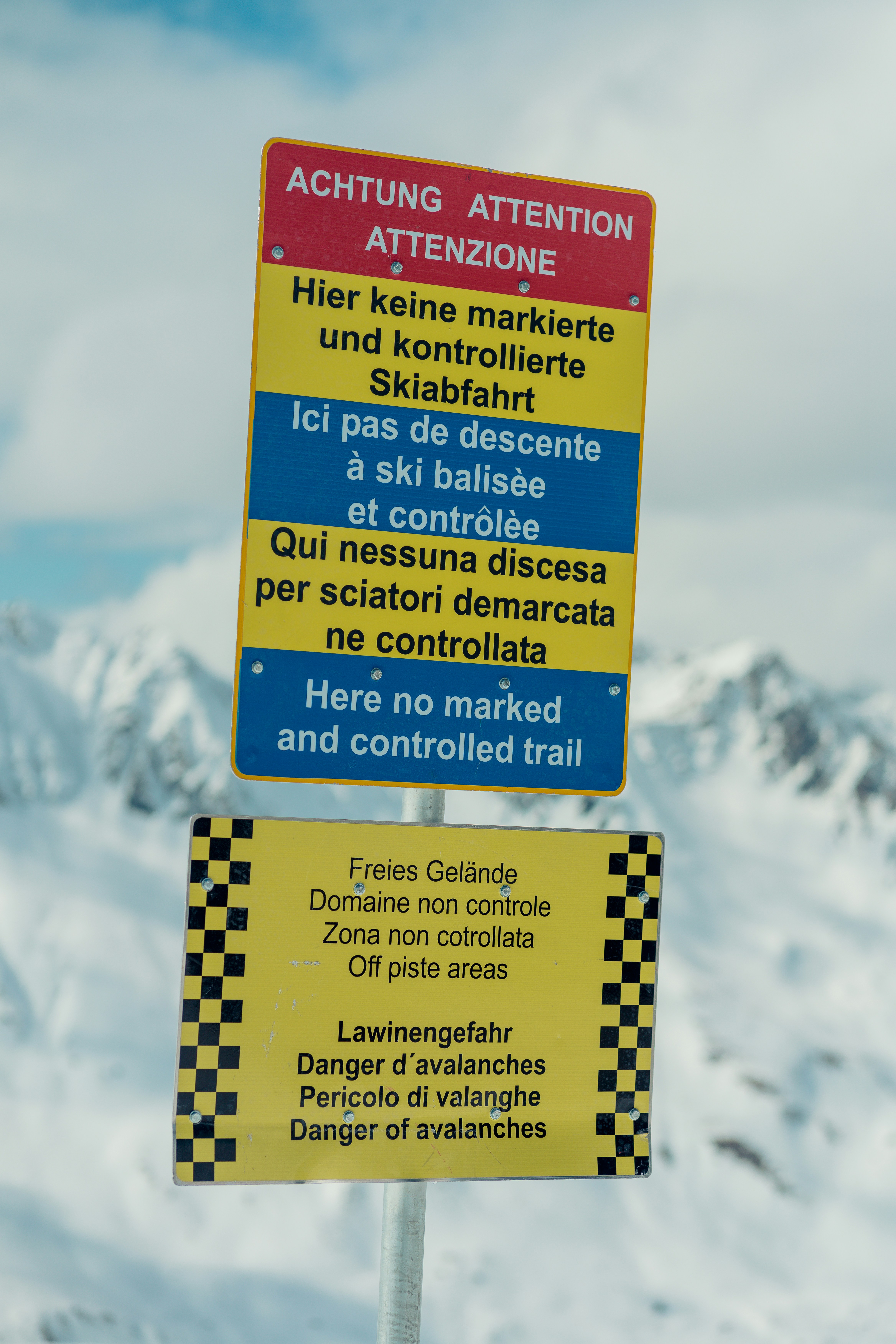 Multi-Layered Alpine Warning Sign Stacks Against Snowy Peaks