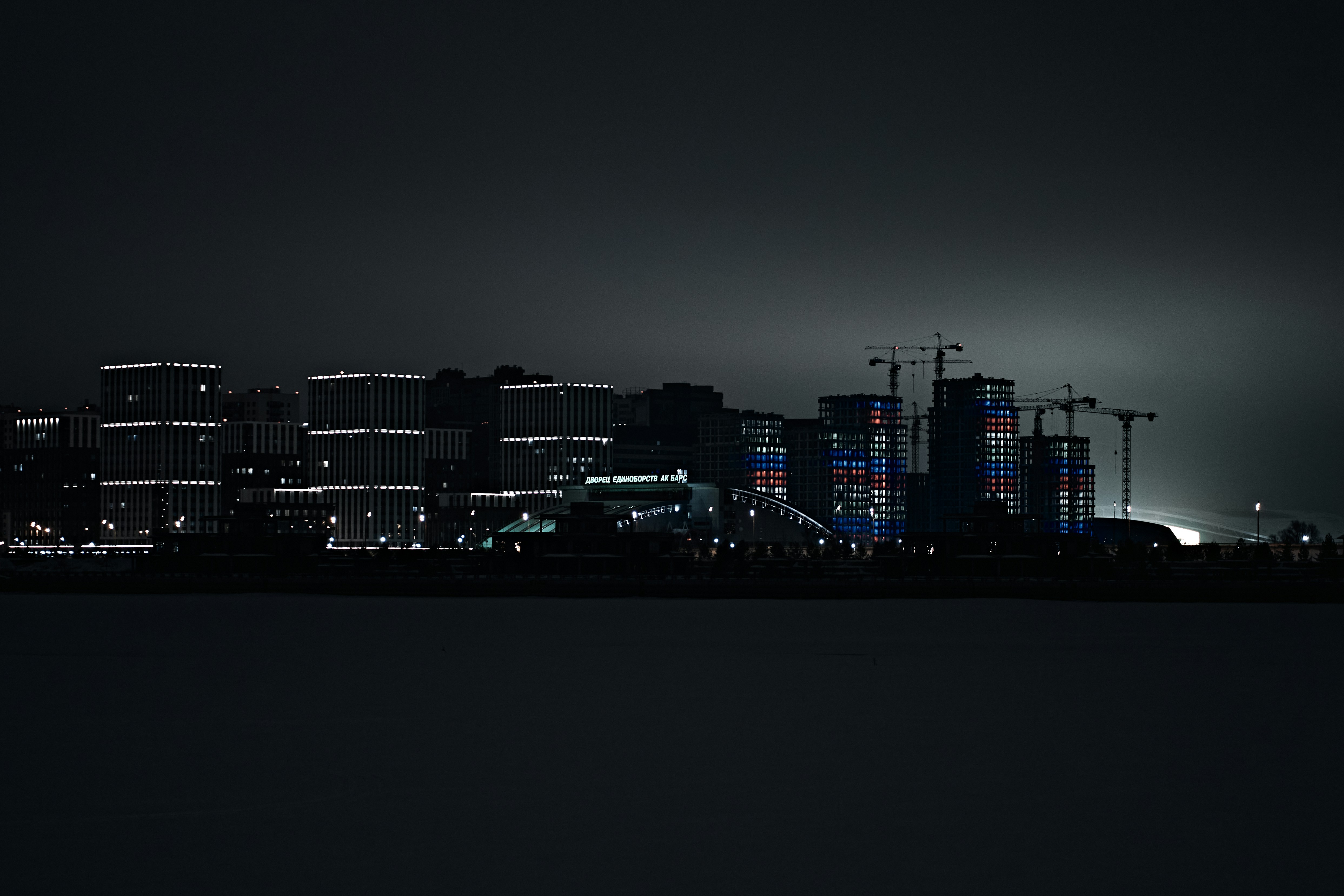 Crane-Lit Horizon: Nighttime Riverside Skyline