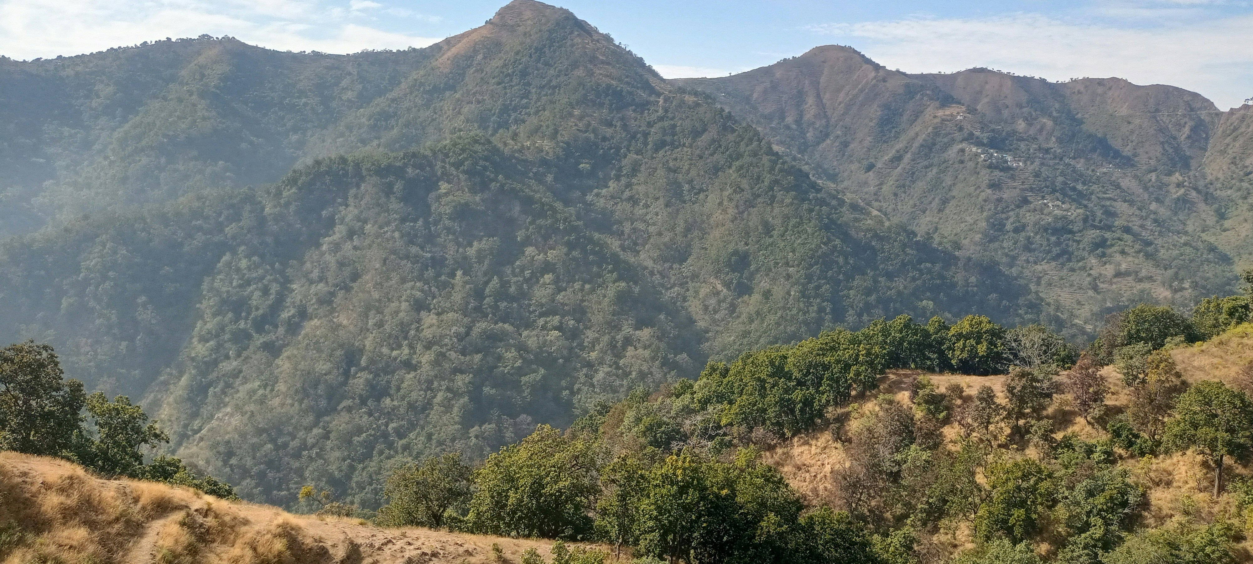 Lush green mountains stretch across the horizon under a clear sky, showcasing the serene beauty of nature's landscape.