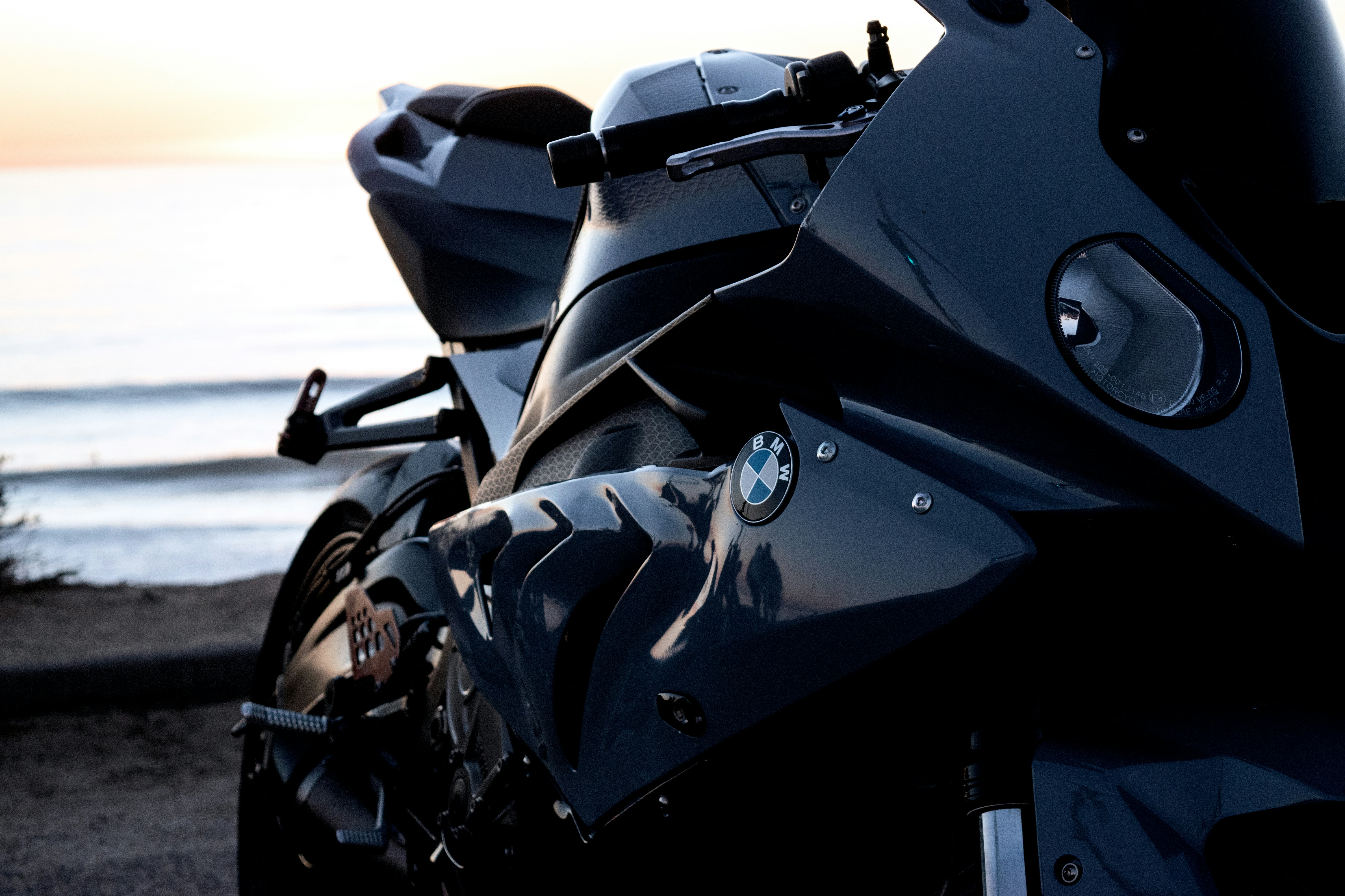 A motorcycle parked on the side of a road near the ocean photo – Free ...
