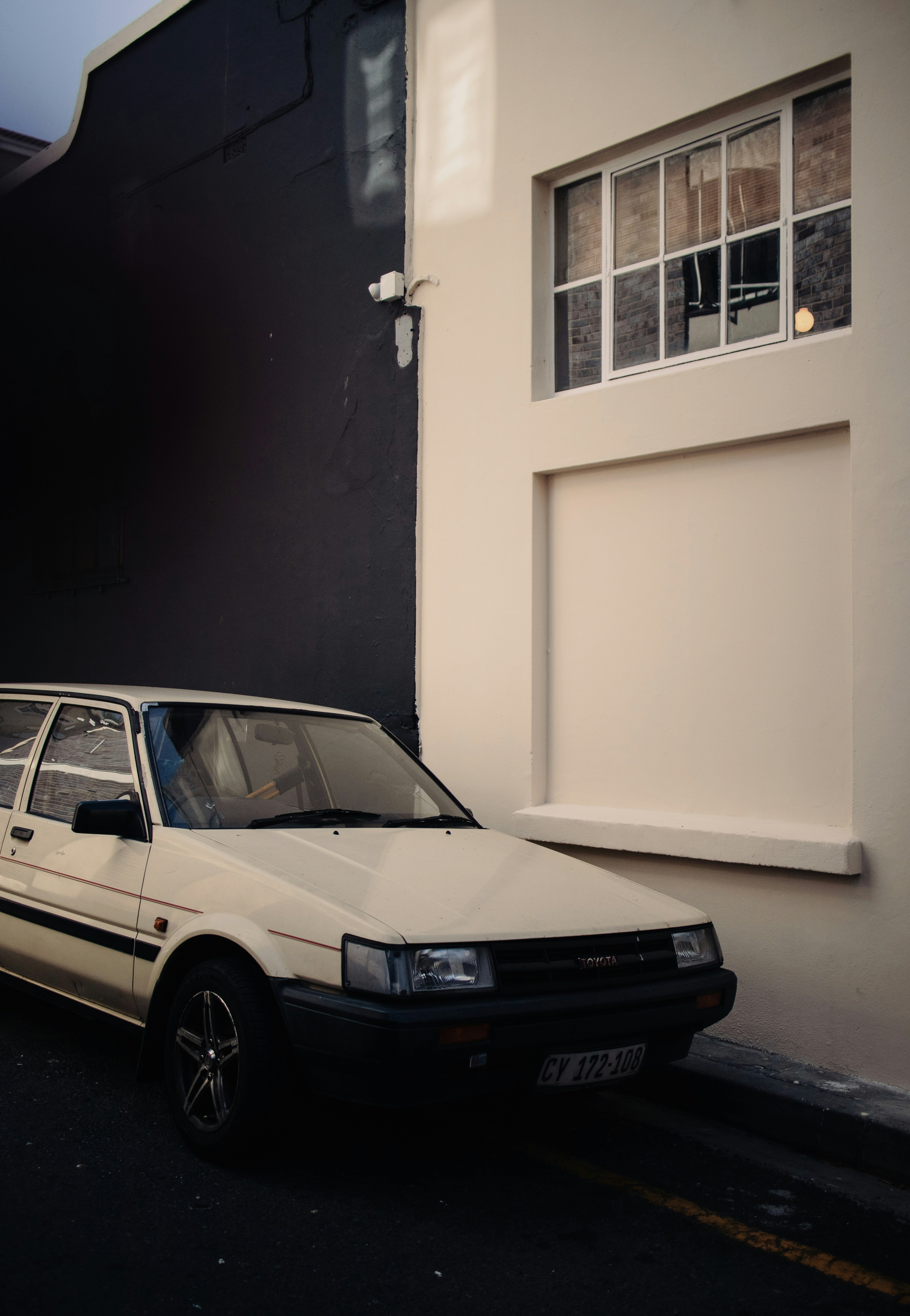 Sunlit Vintage Sedan Quietly Anchors a Two-Tone Urban Wall