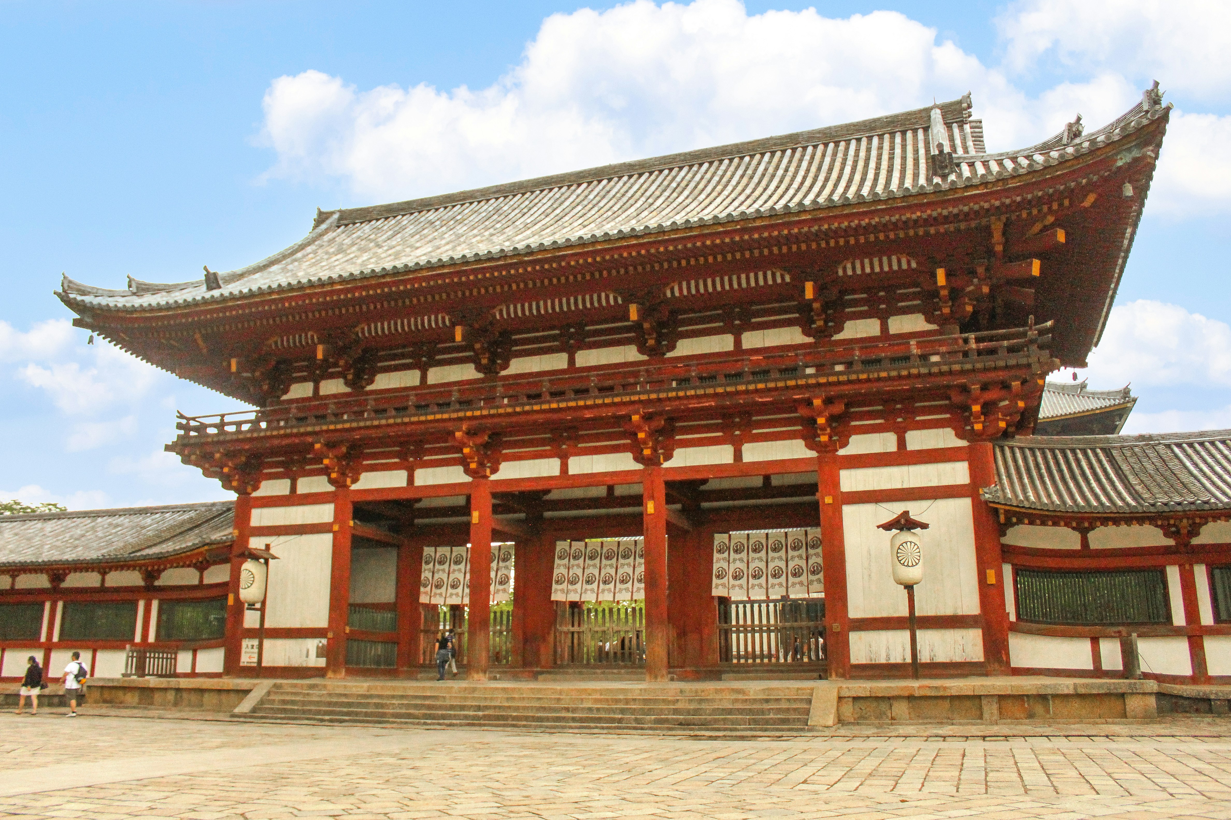 Historic temple entrance showcasing intricate wooden craftsmanship and vibrant colors against a blue sky.