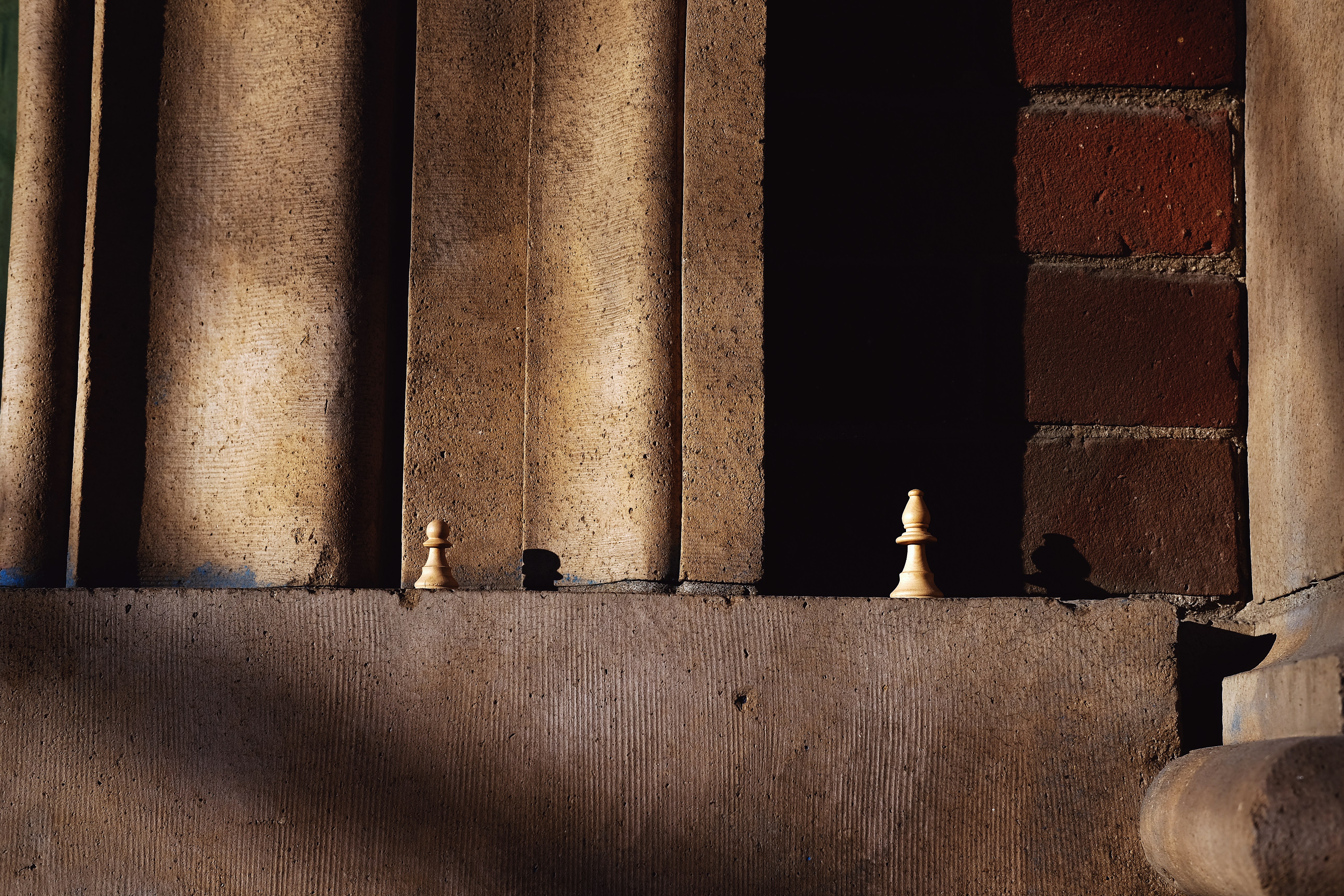 Pawns in the Dusk: Tiny chess figures on a weathered stone ledge