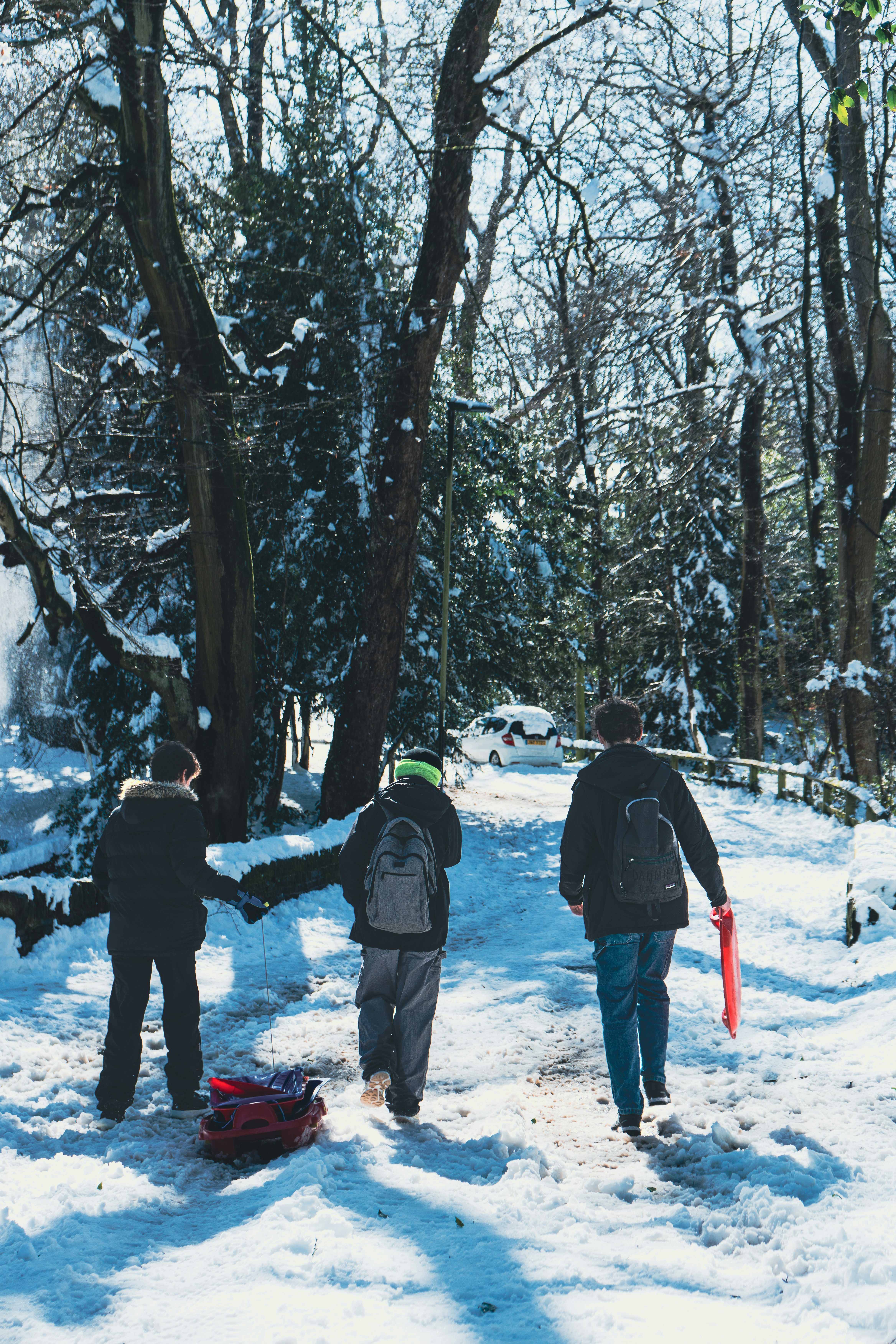 Snowbound Trail: Three Friends Trek Toward a Quiet Car at Dusk