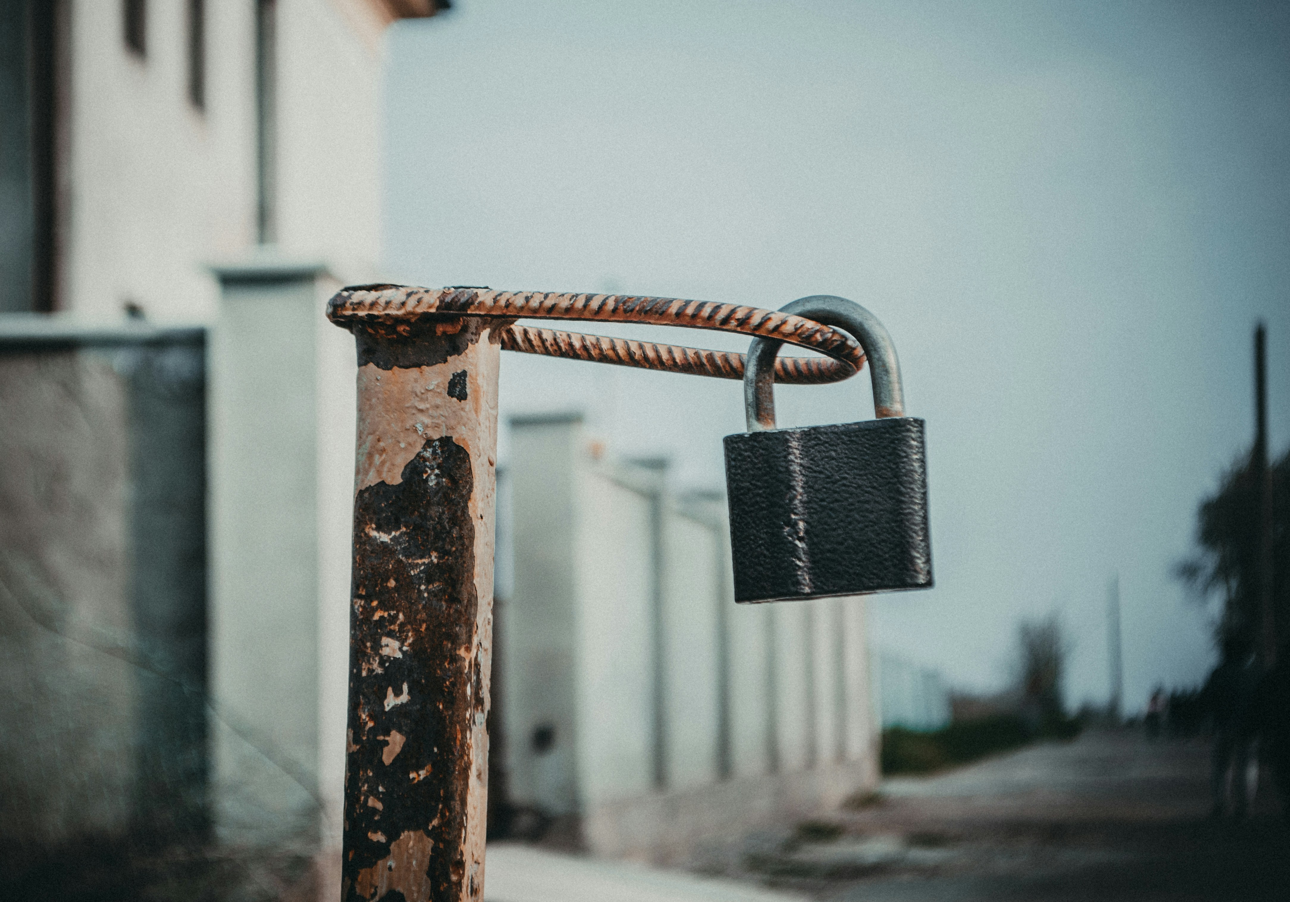 A padlock attached to a metal pole near a building photo – Free ...
