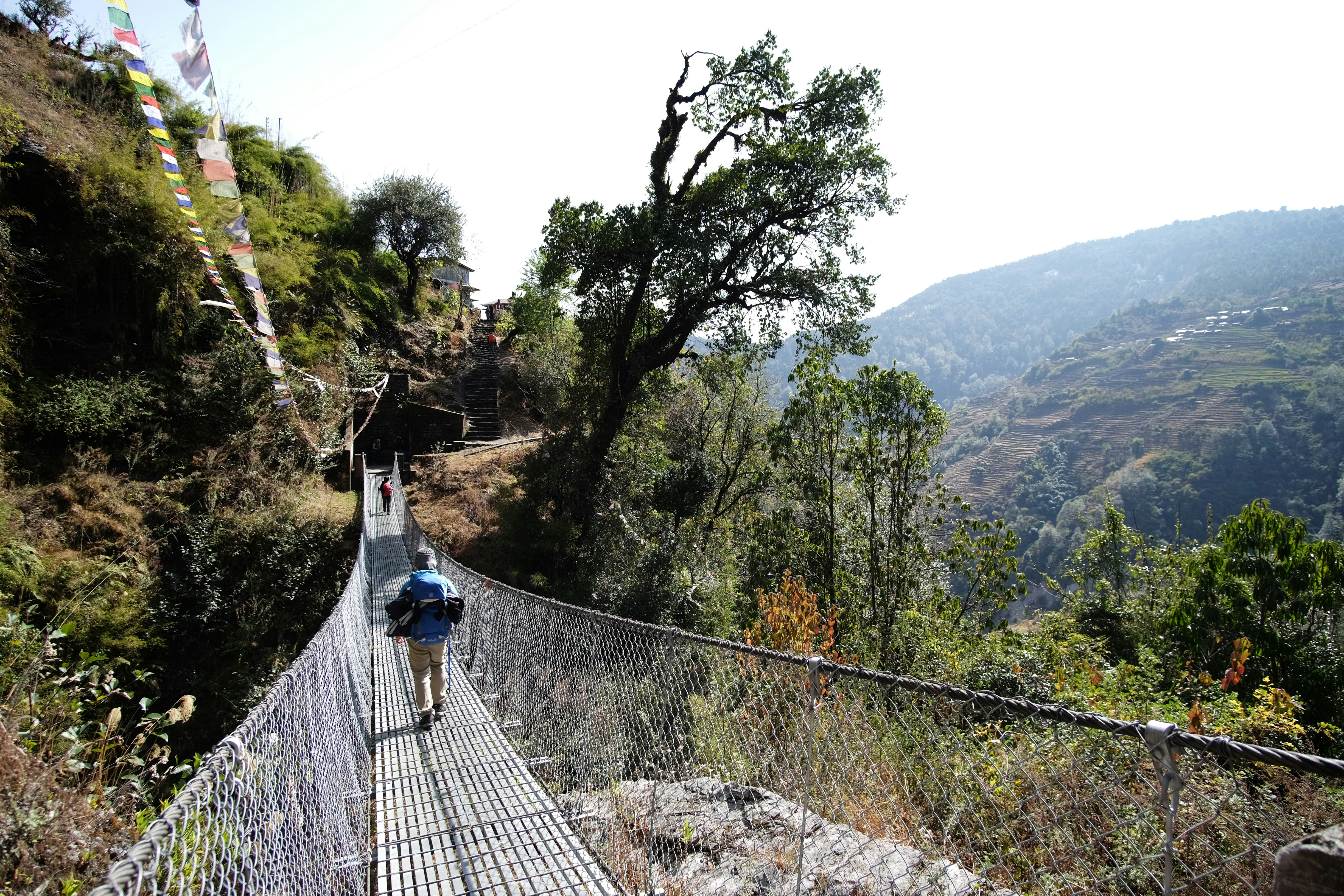 A man walking across a suspension bridge in the mountains photo – Free ...