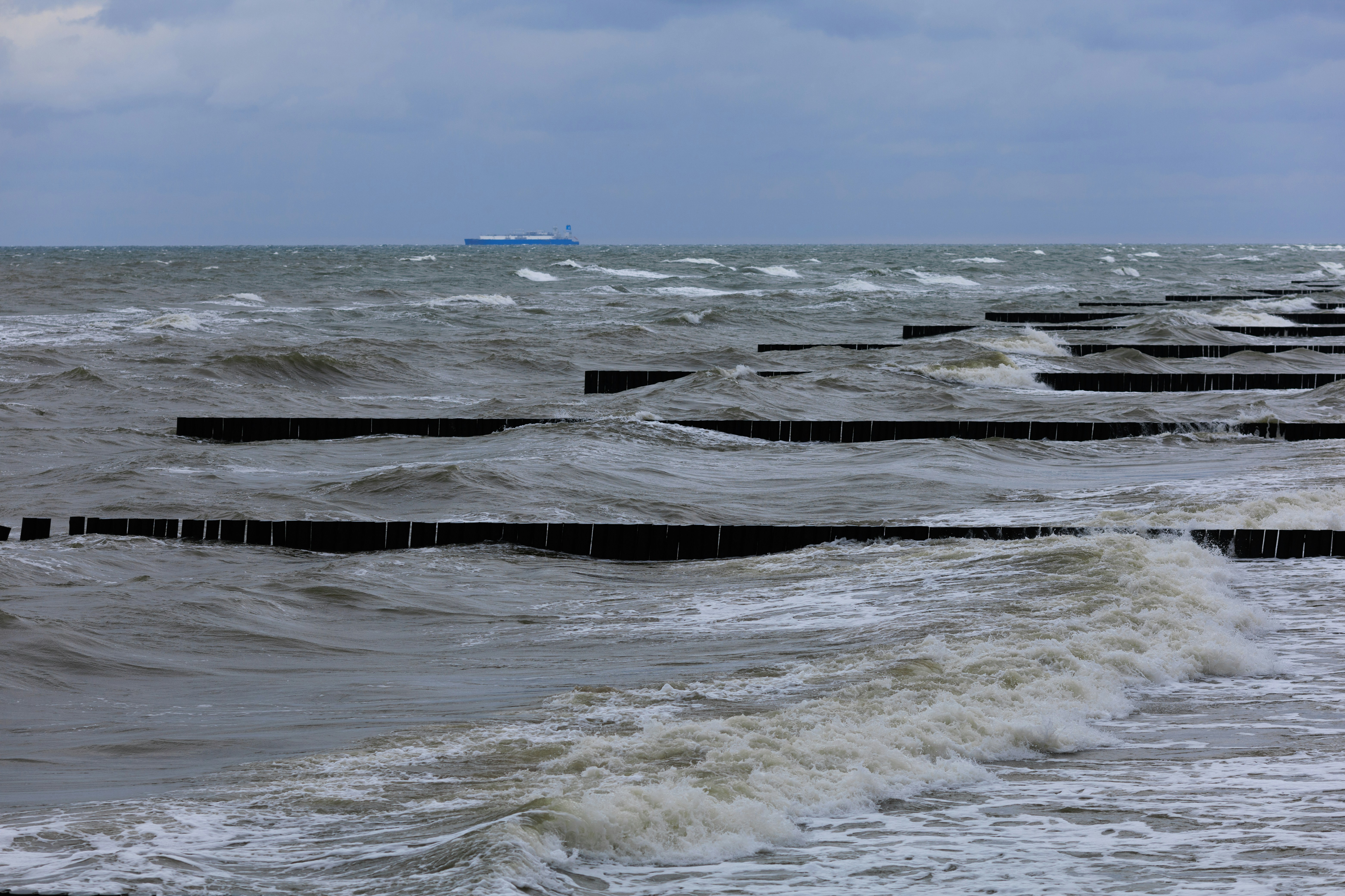 Parallel Breakwaters Meet a Distant Freighter on a Gray Sea