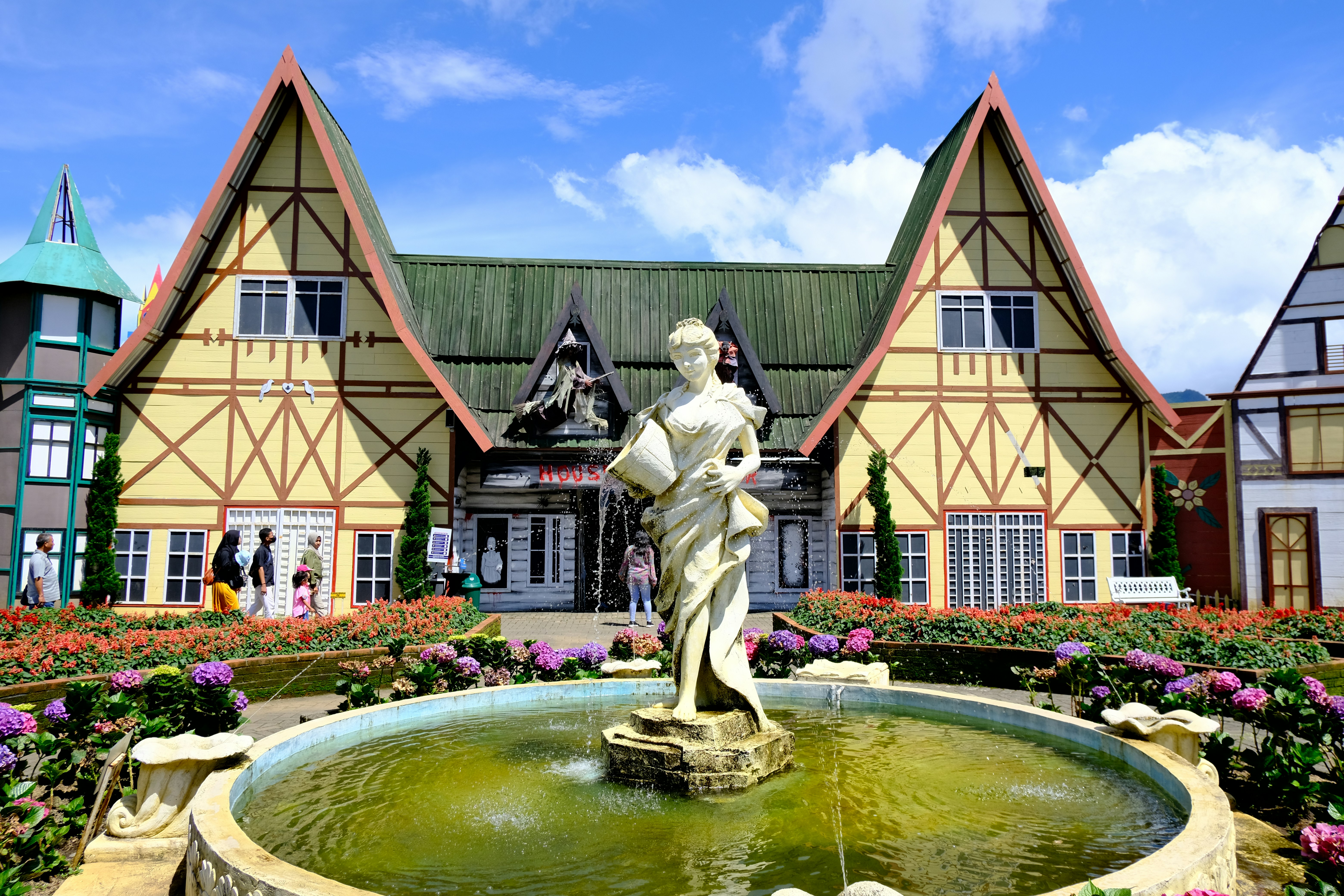 A fountain in front of a house with flowers around it photo – Free ...