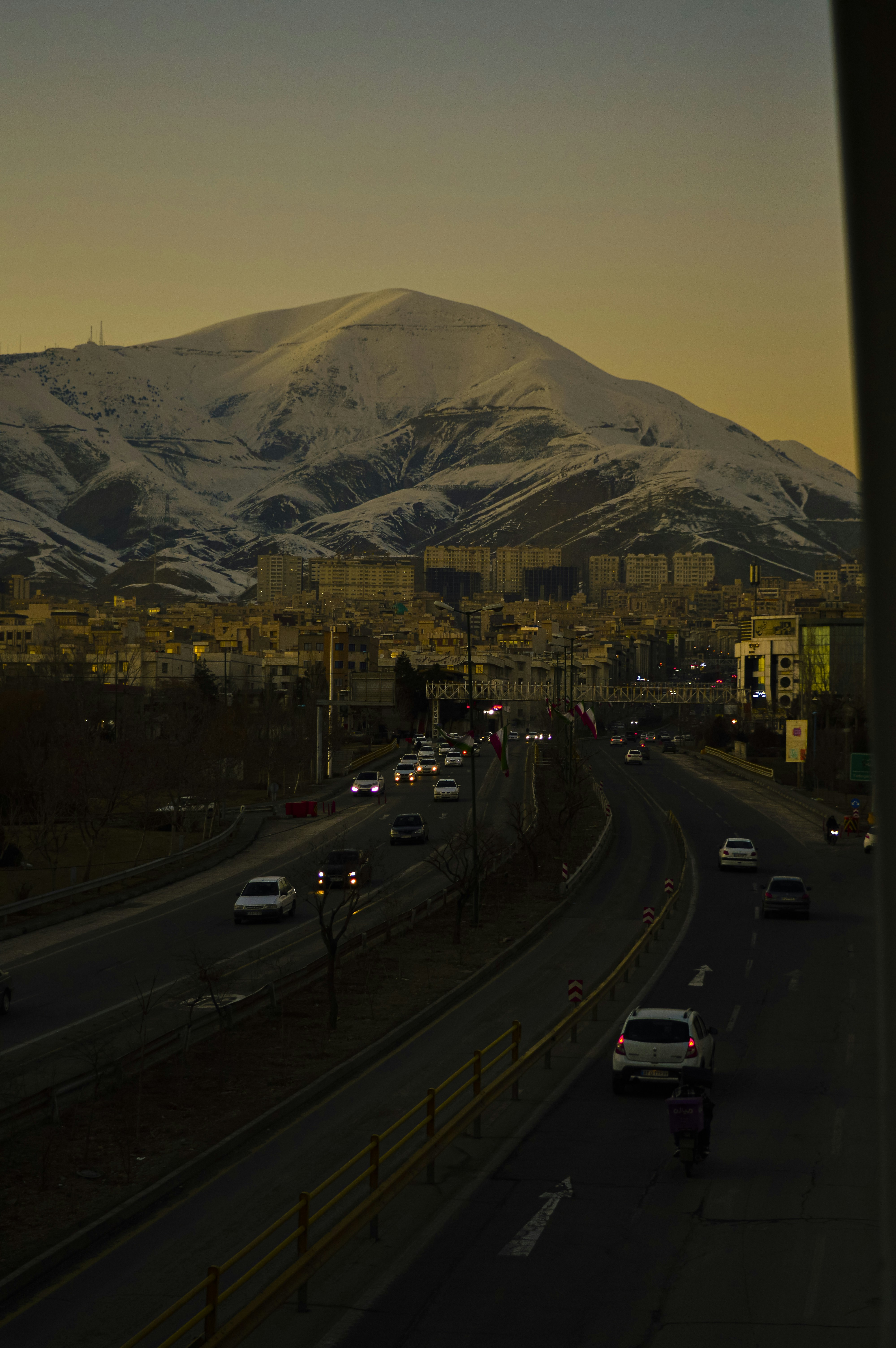 Golden Hour Convergence: City Artery Beneath a Snow-Crowned Summit