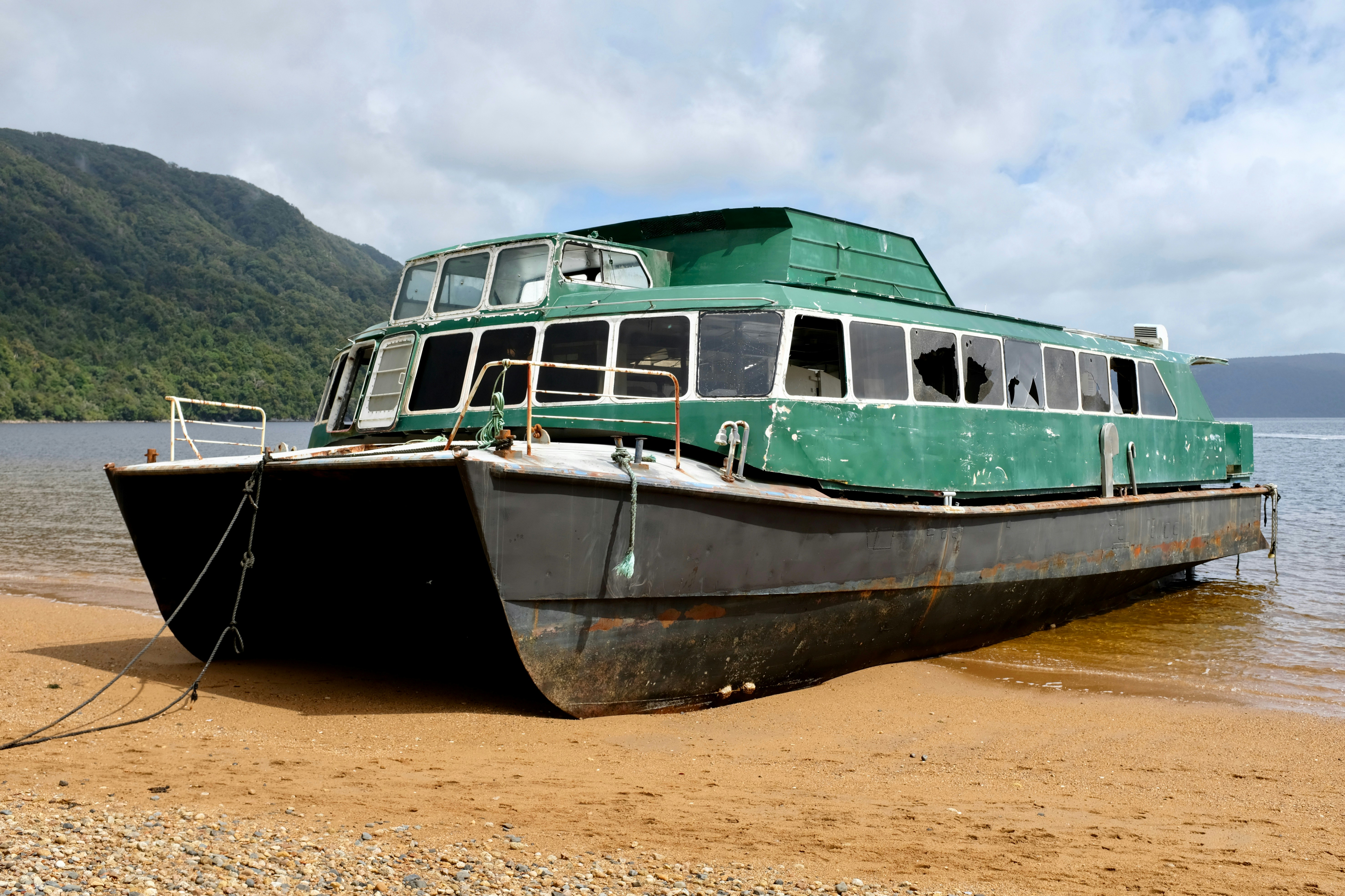 Green-Hulled Vessel Resting on a Quiet Shoreline