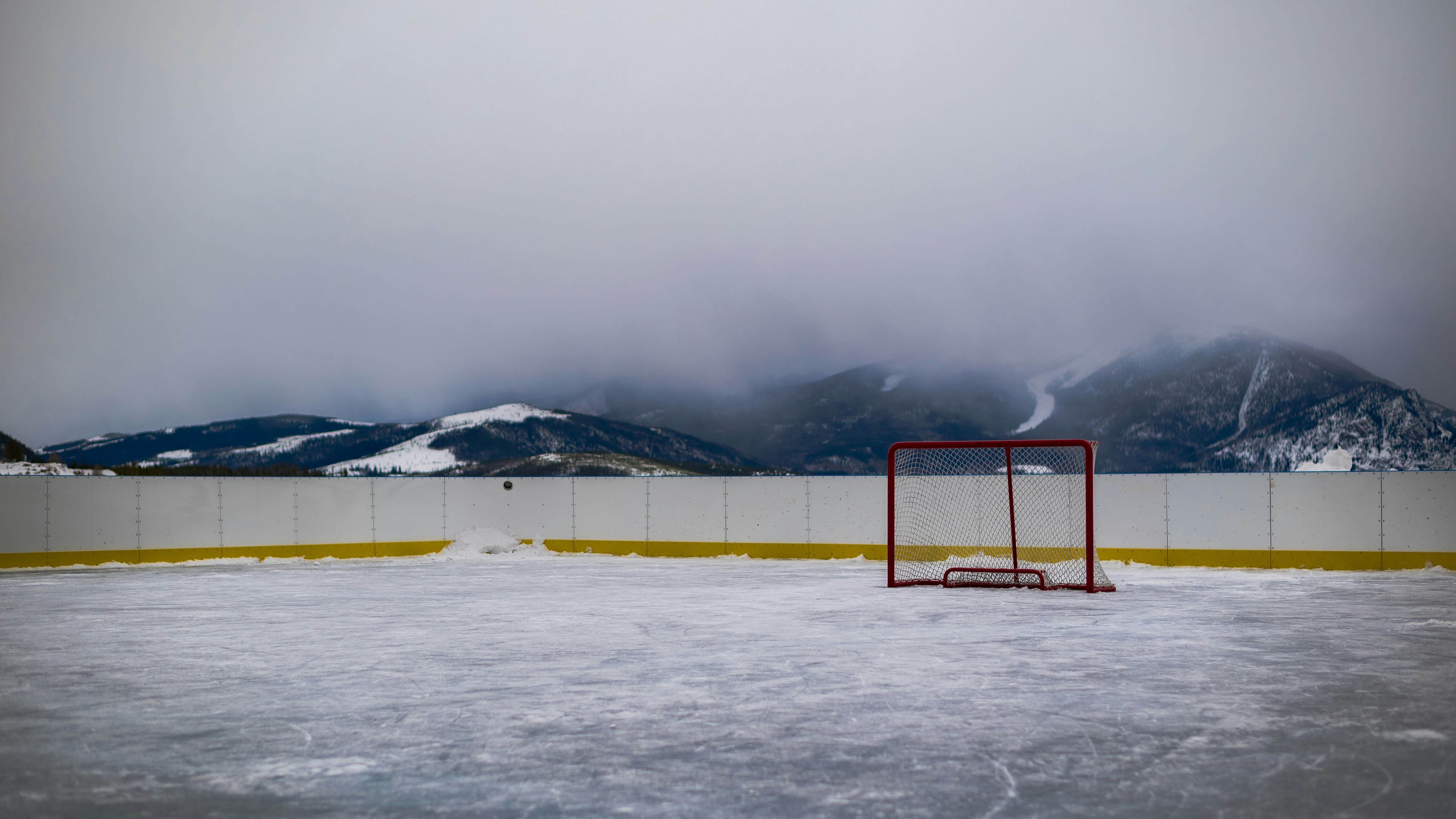 A hockey goal on an ice rink with mountains in the background photo ...