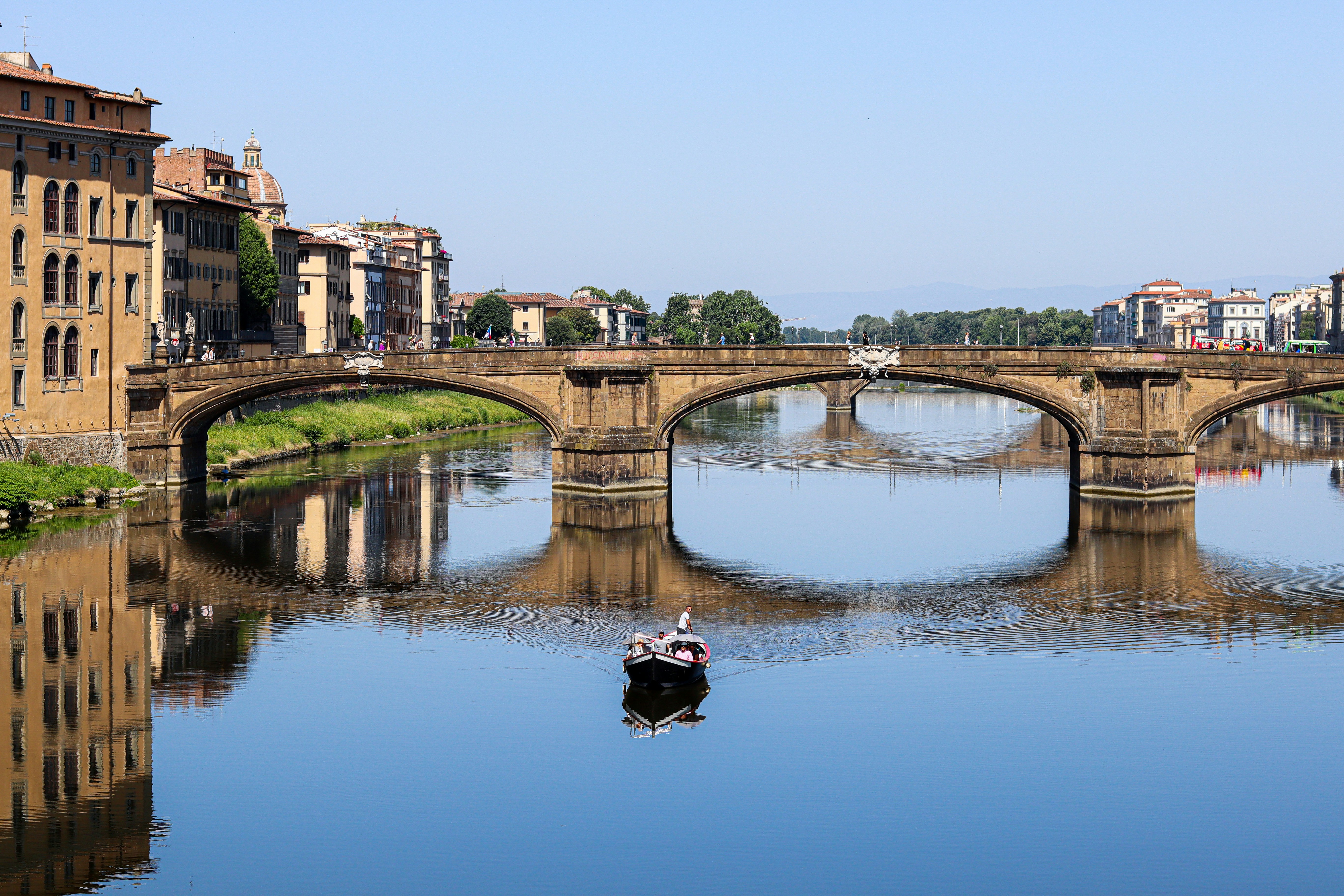 A boat floating on a river next to a bridge photo – Free Florence Image ...