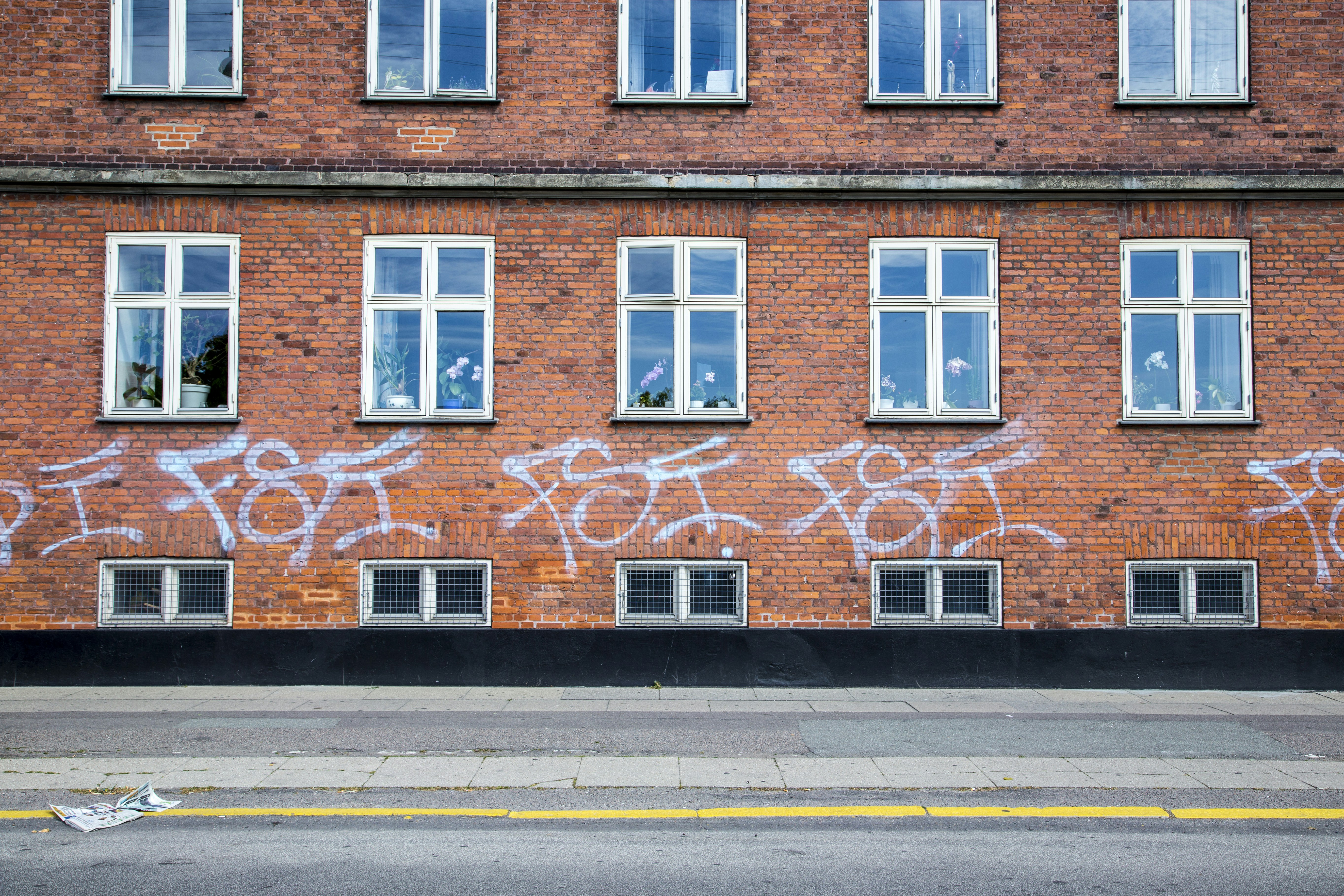 a red brick building with white windows and graffiti on it
