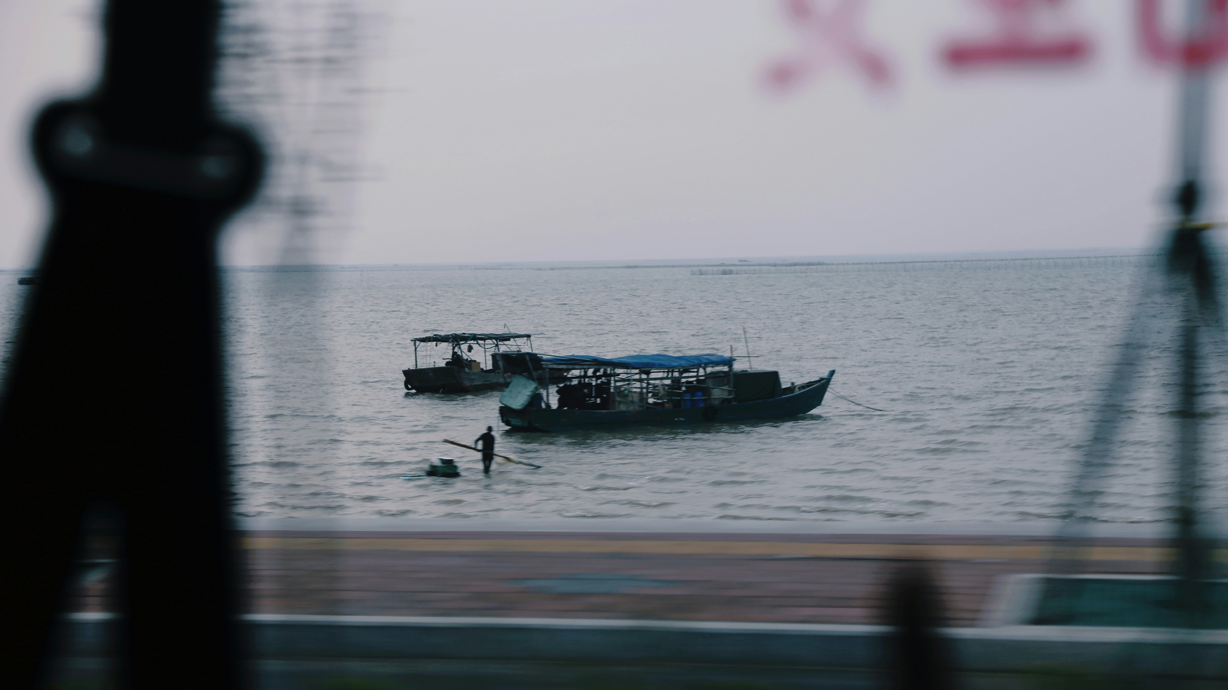 Two boats anchored on a calm sea with a soft horizon.