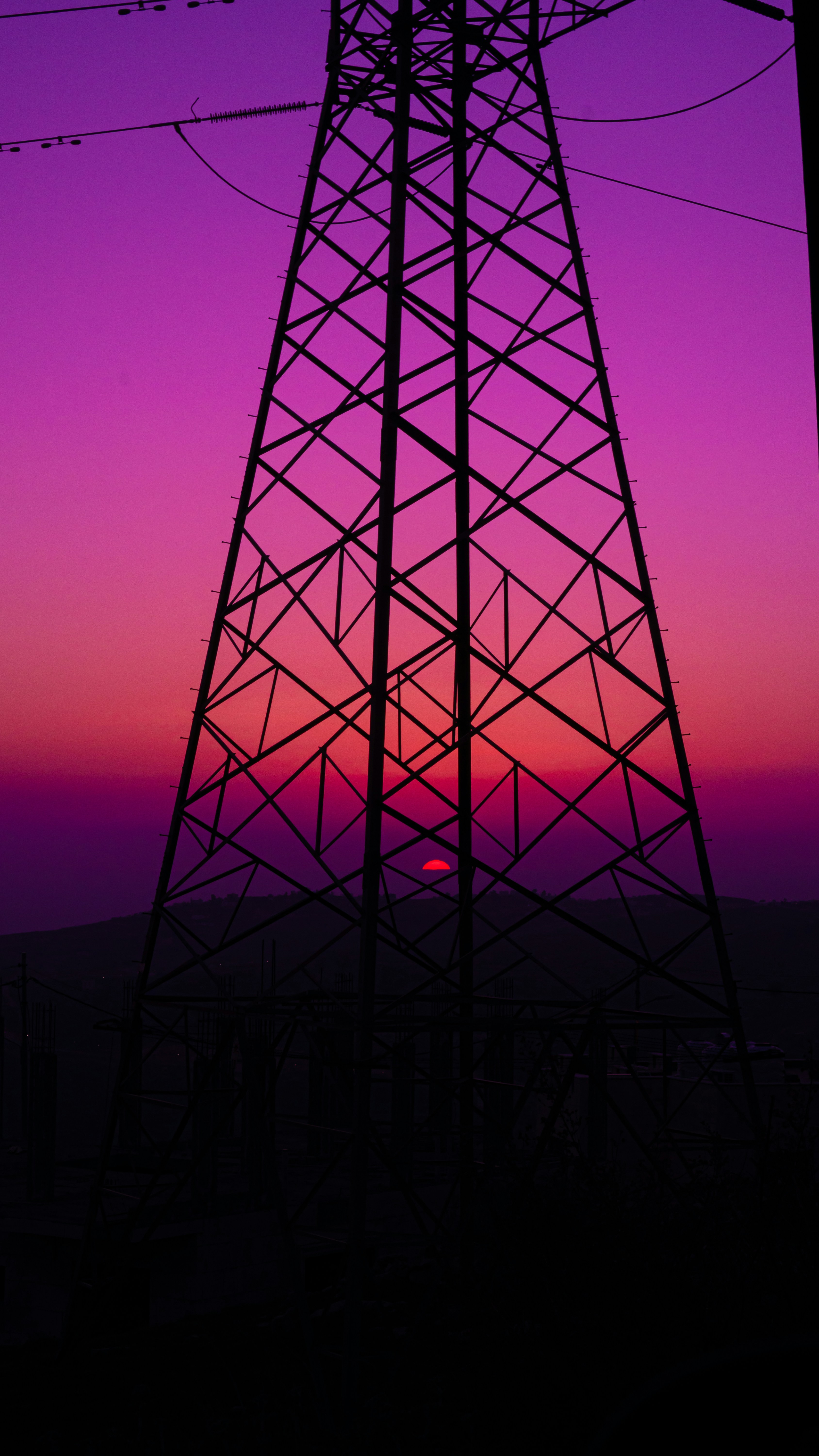 the sun is setting behind a power tower