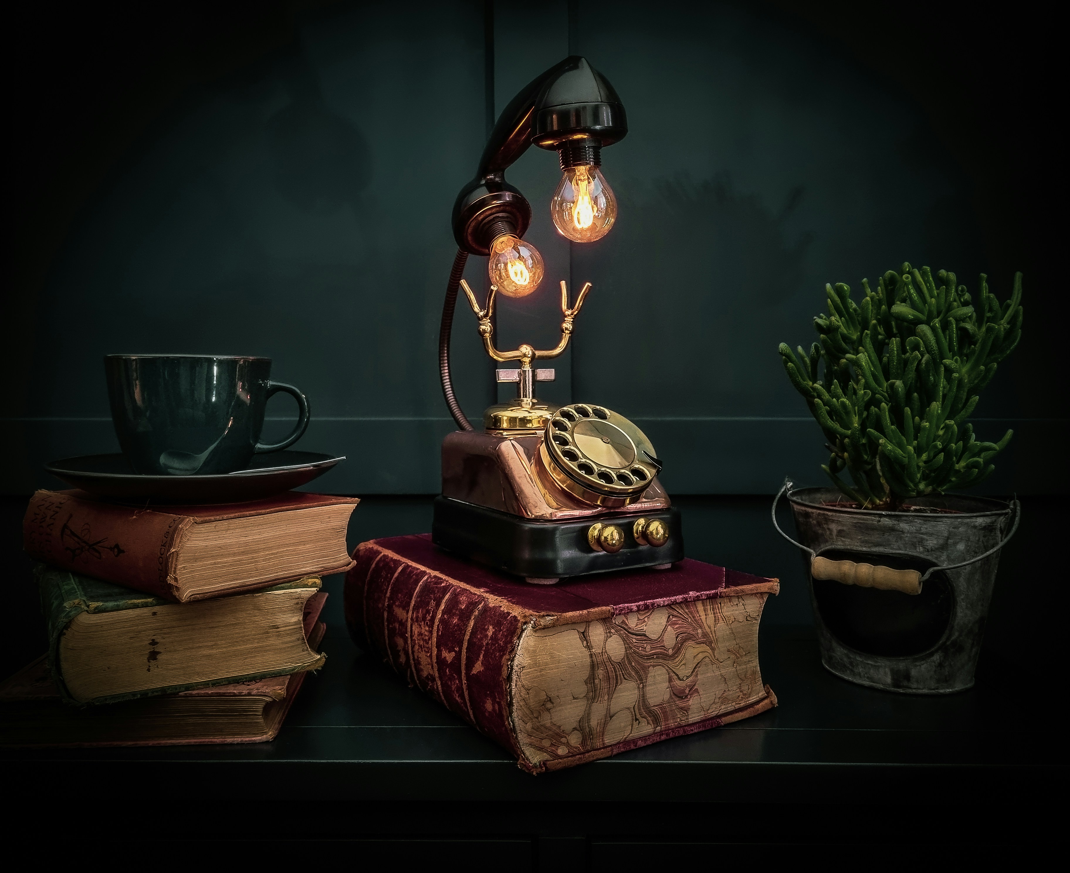 Upcycled vintage copper &amp; brass telephone lamp with old books and a cup of tea | a table topped with books and a telephone