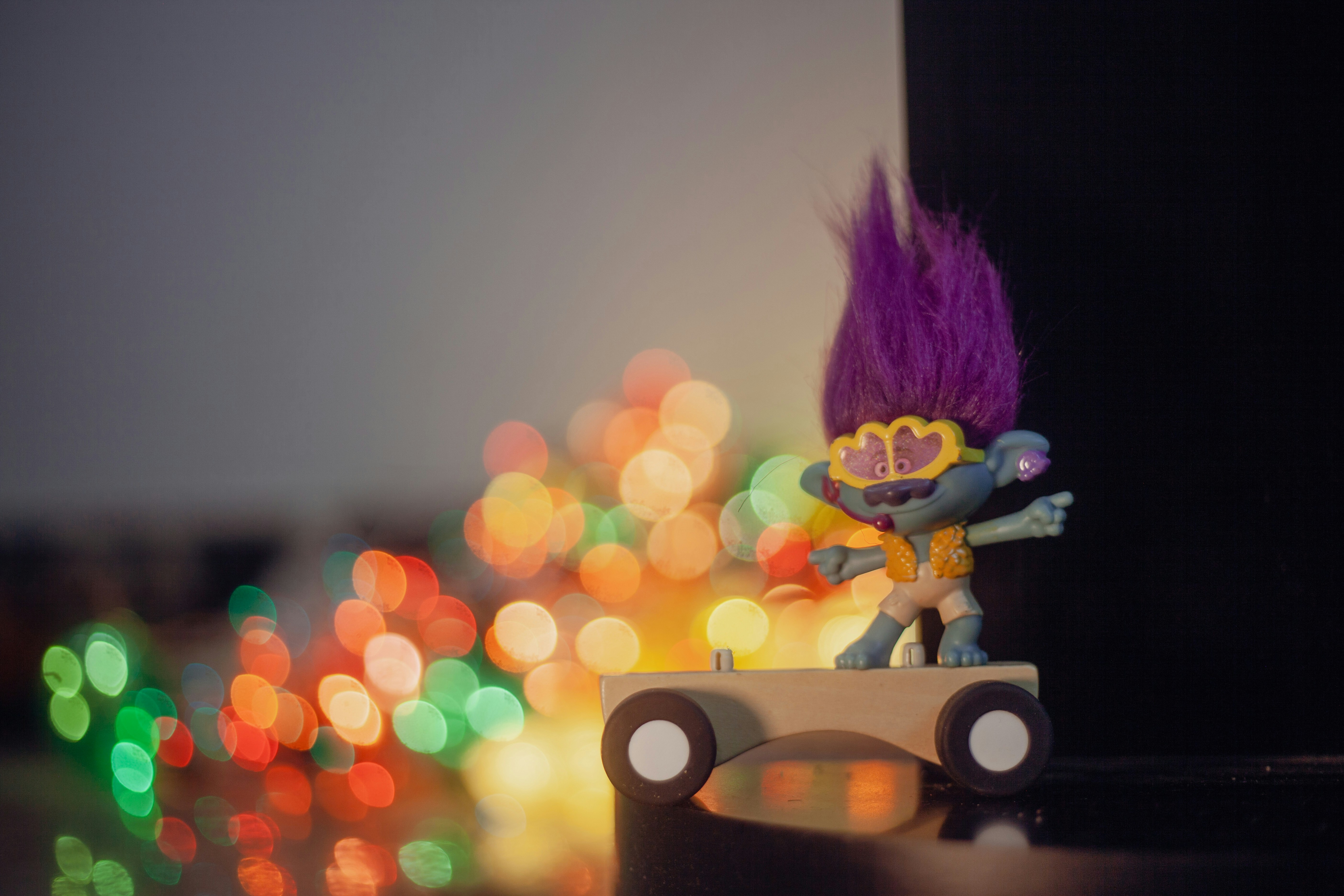a small toy with purple hair sitting on top of a table