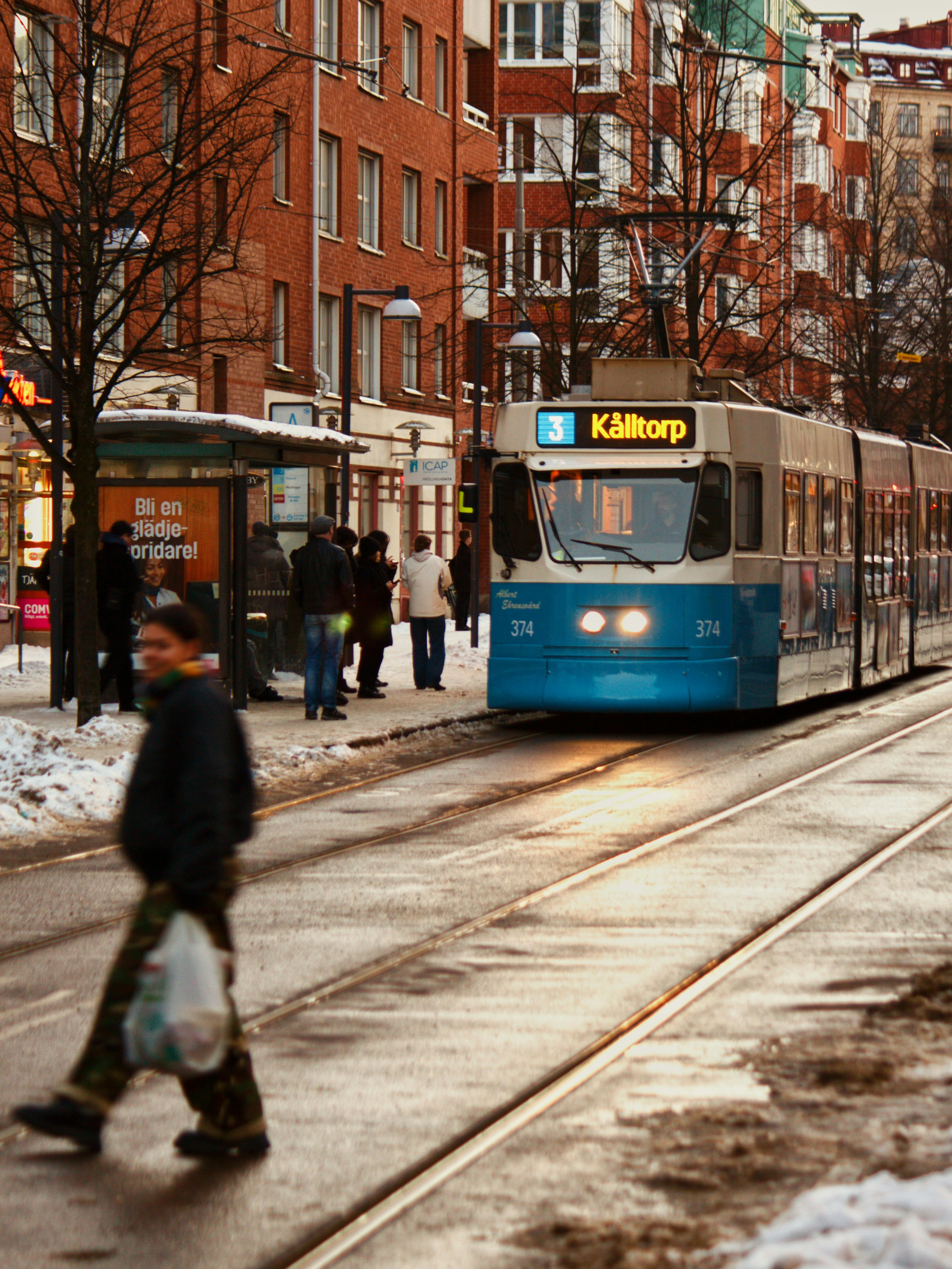 Blue tram gliding through a snow-dusted urban street