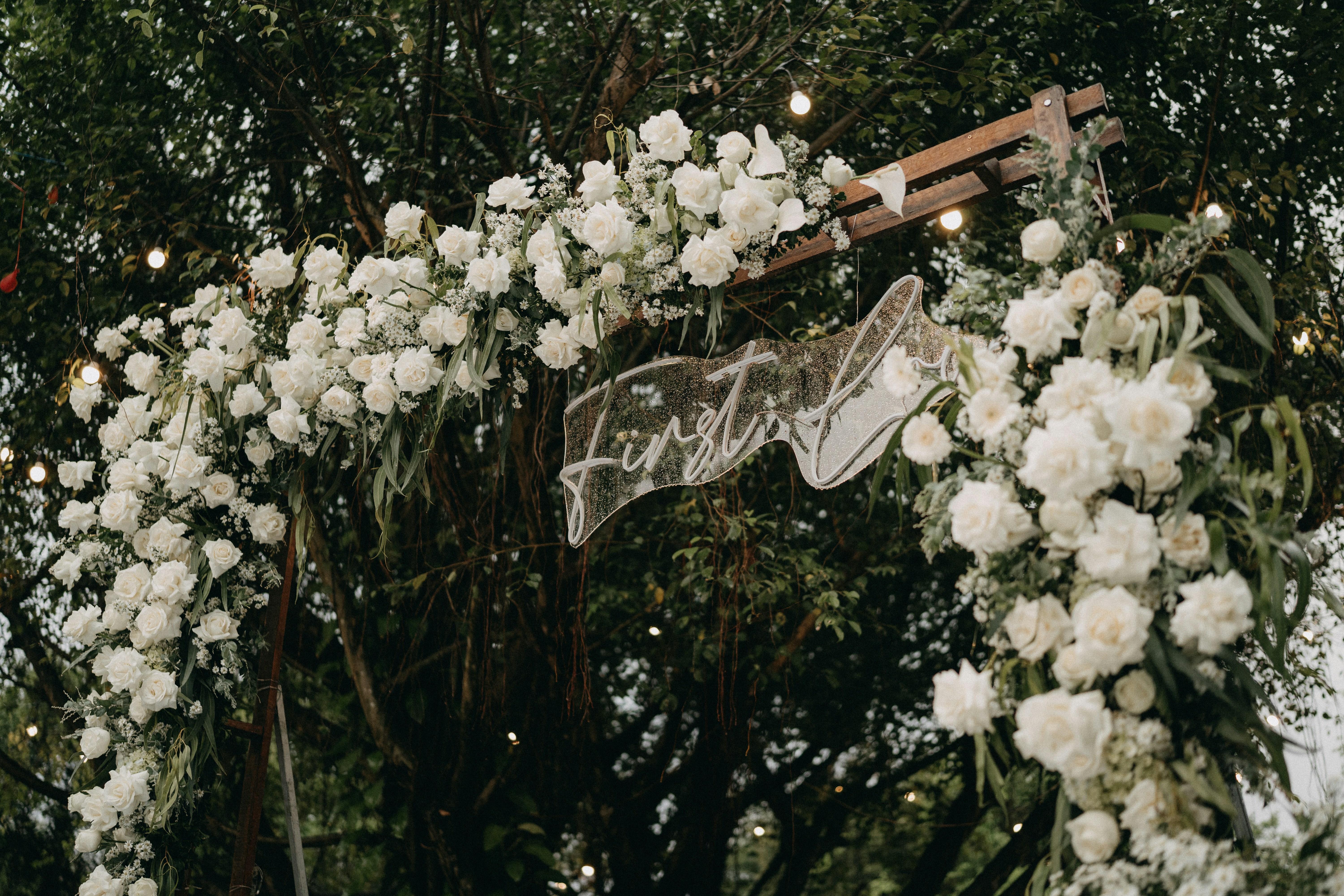 Ivory Floral Arch Framed by Warm Lights with a Just Married Banner