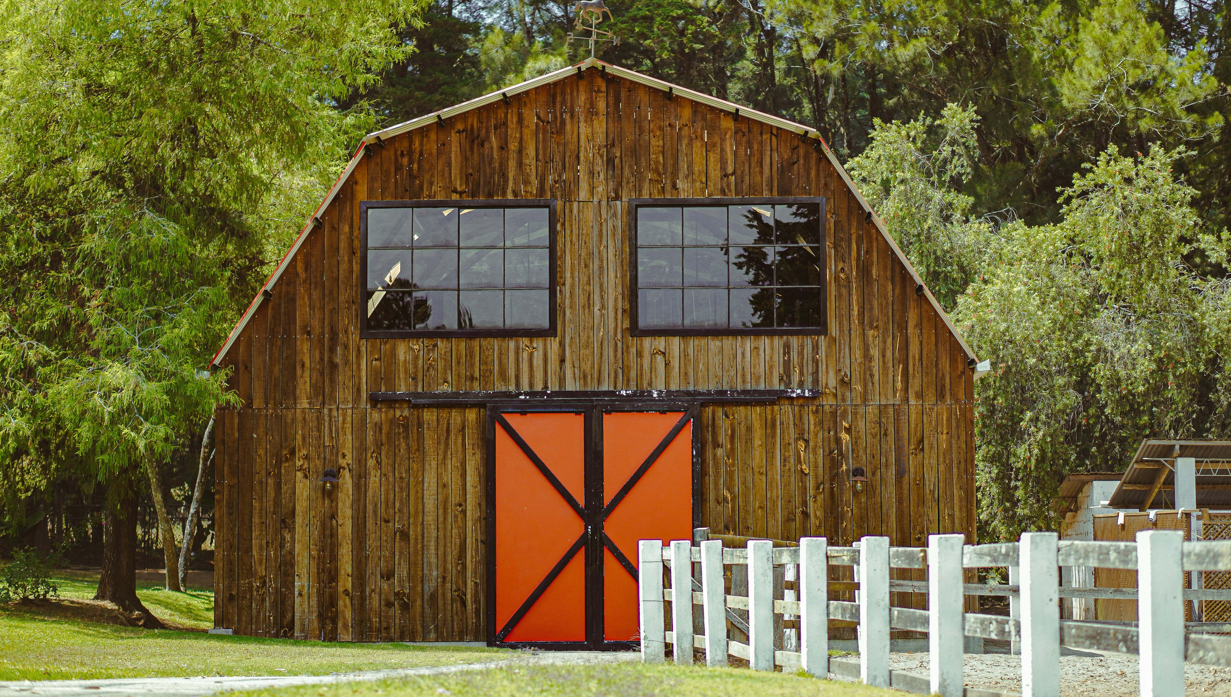 Weathered Barn with Bold Orange Doors Framed by White Fence