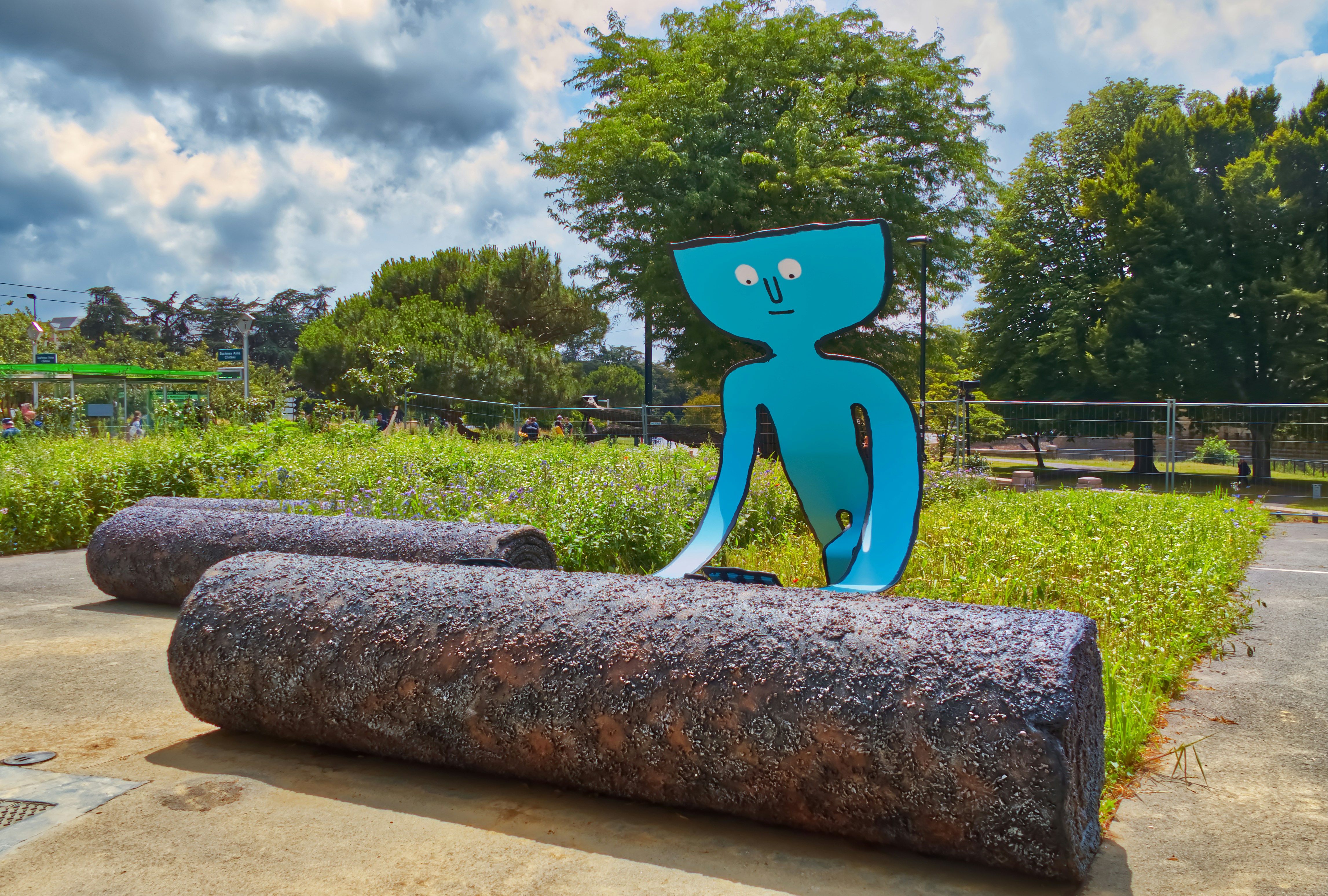 Blue Silhouette Guardian Over Weathered Logs in a Sunlit Park