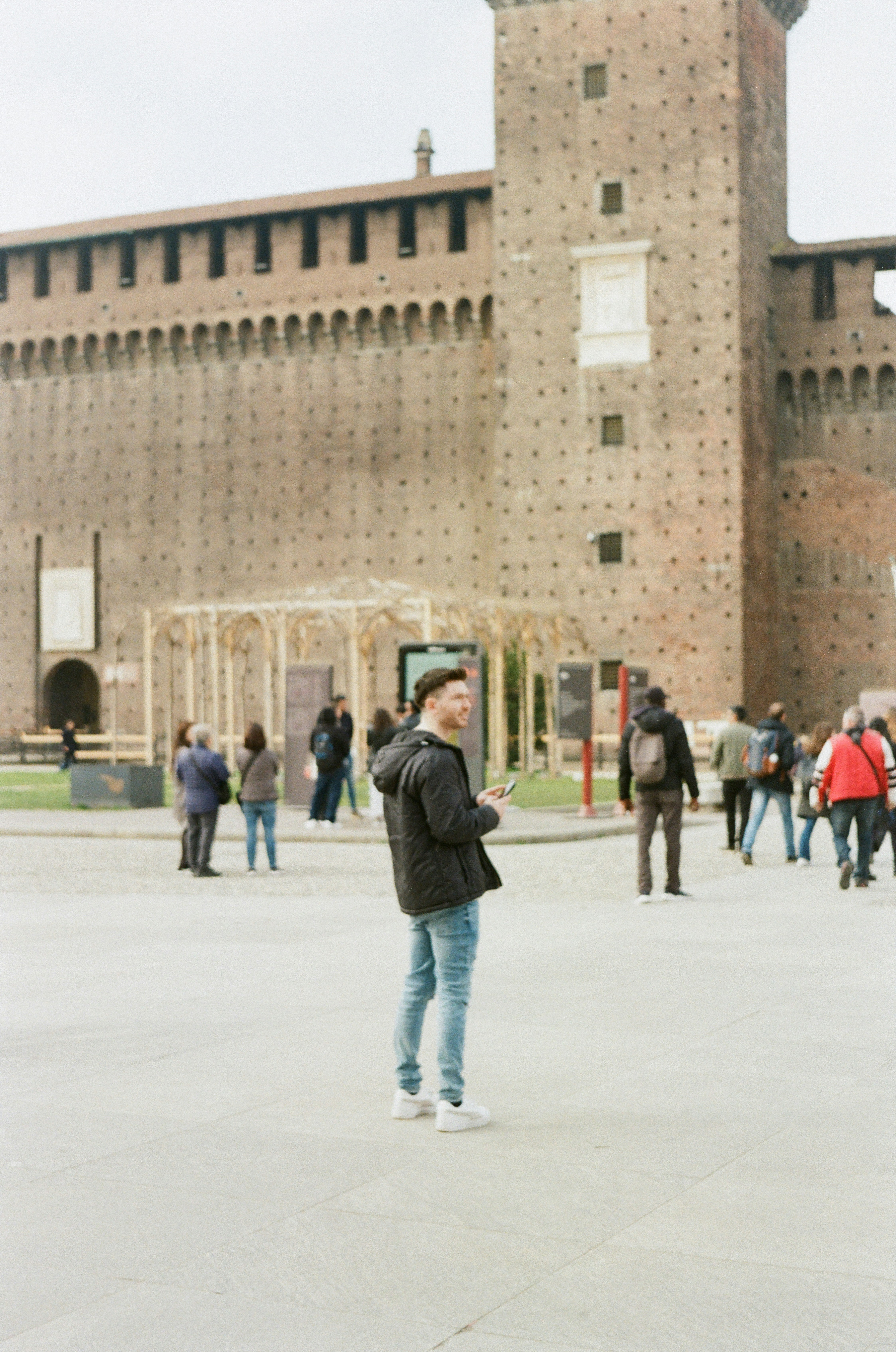 A man standing in front of a tall brick building photo – Free Milan ...