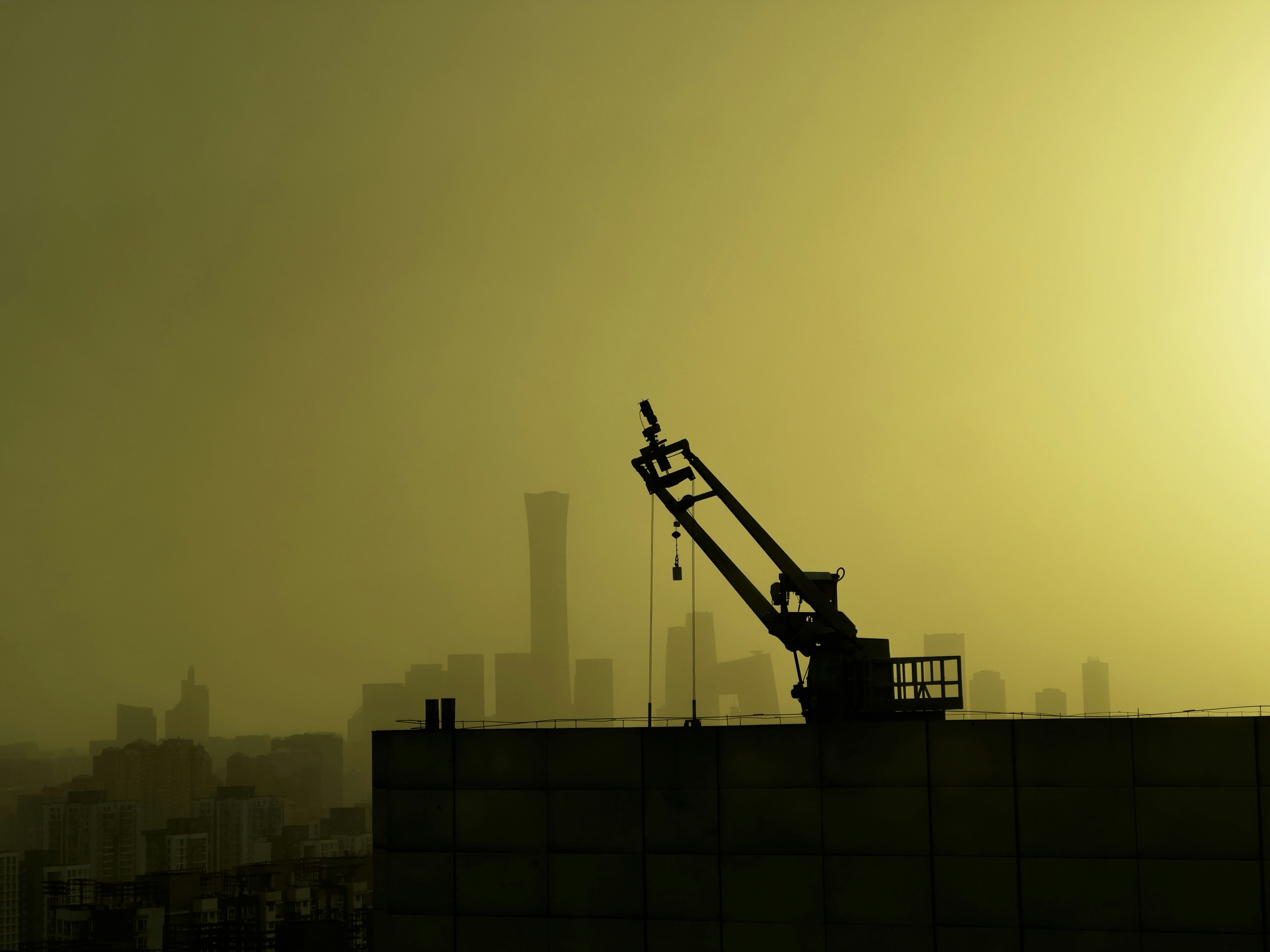 Crane Silhouette Over a Yellow-Hued City Horizon