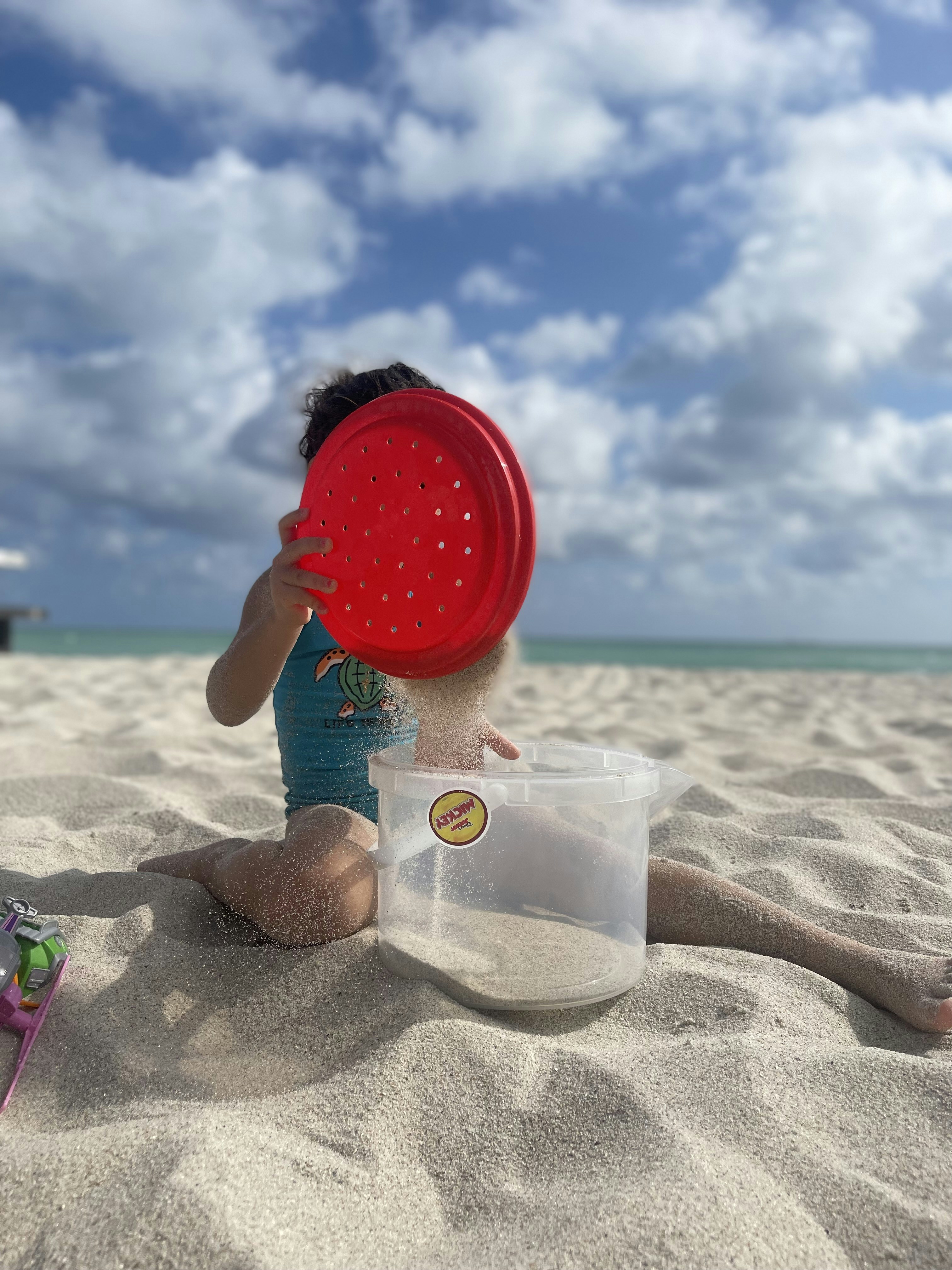 A little girl sitting in the sand with a frisbee photo – Free ...