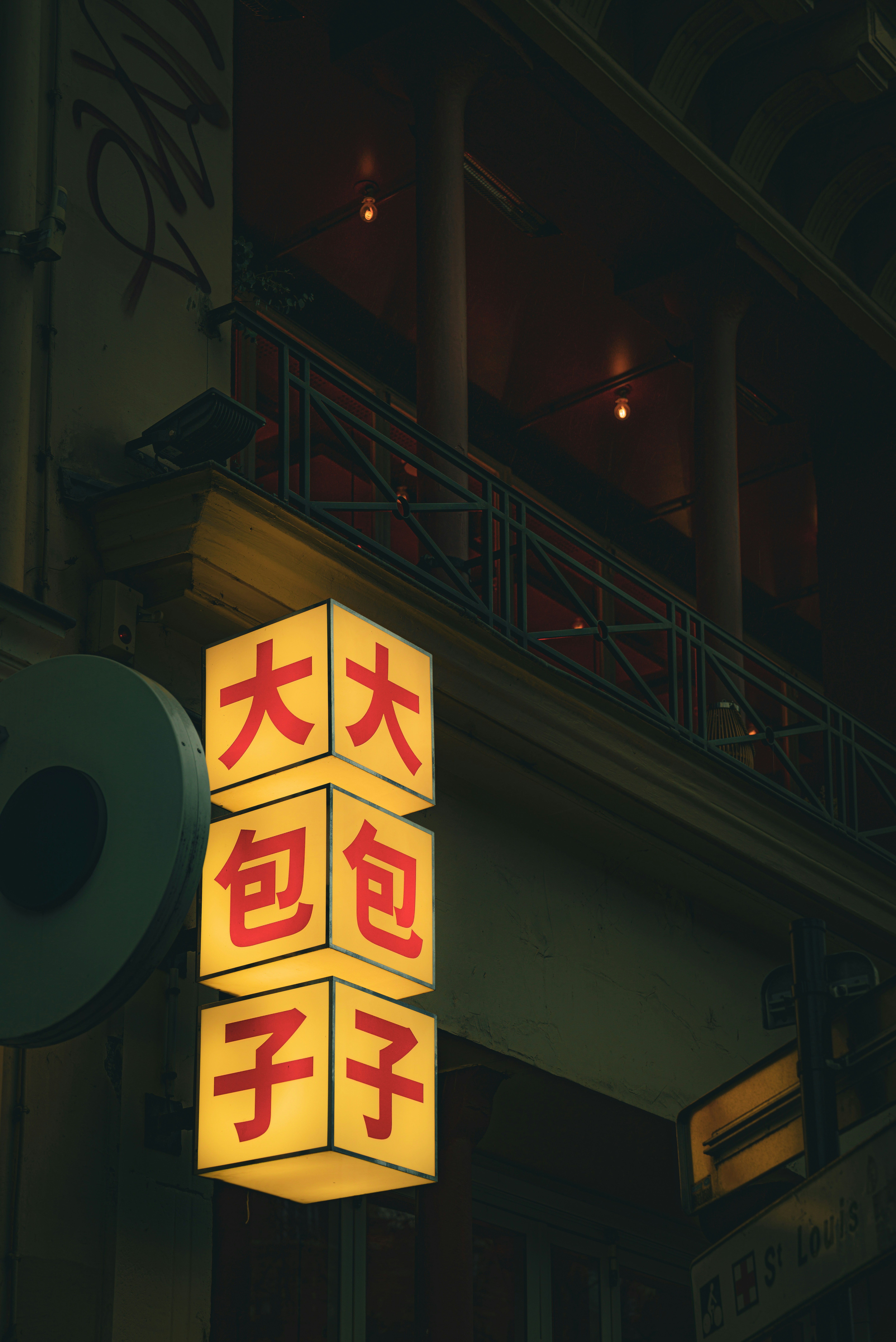 A building with a lit up sign hanging from it's side photo – Free ...