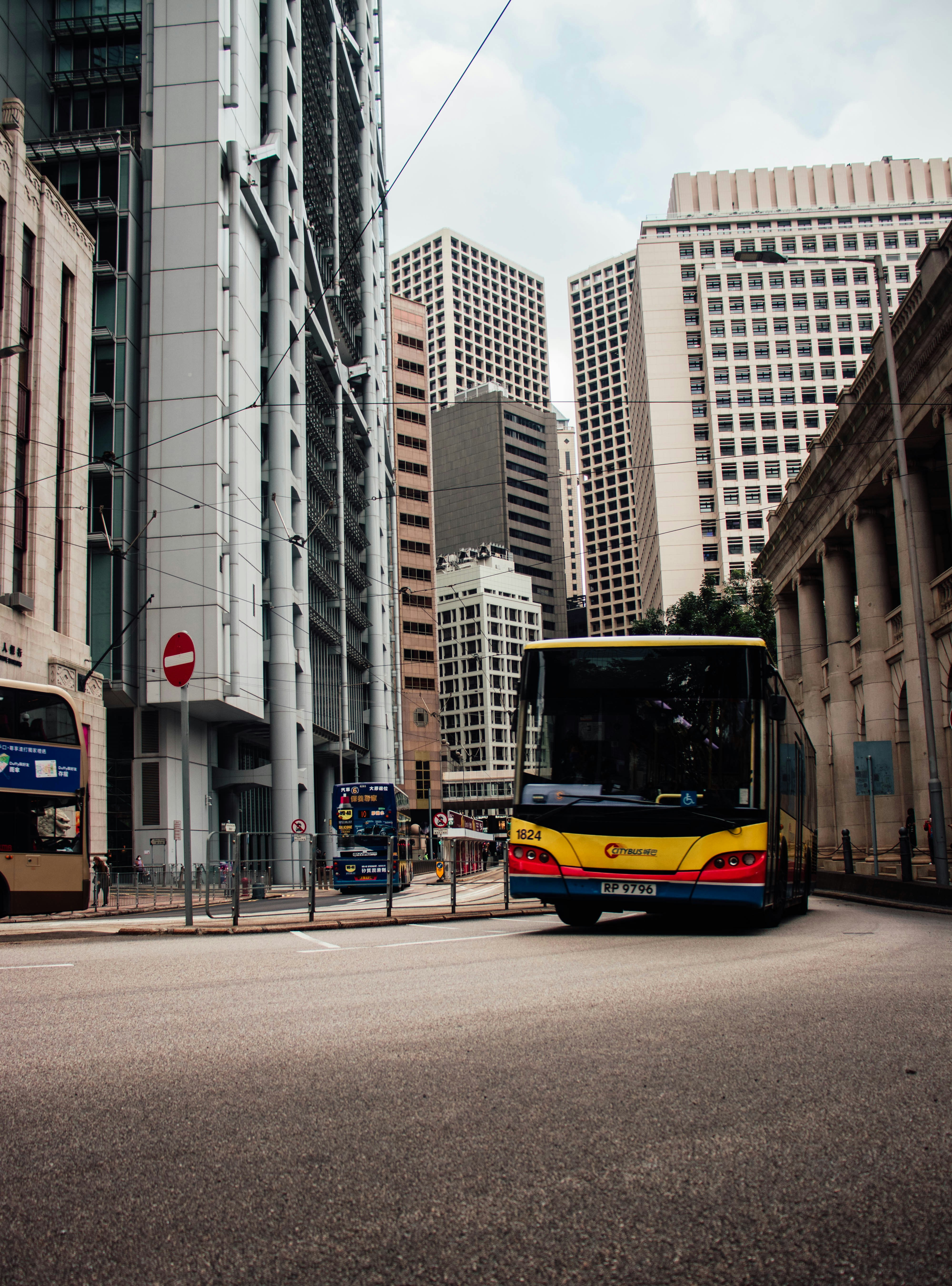 A bus driving down a street next to tall buildings photo – Free Bus ...