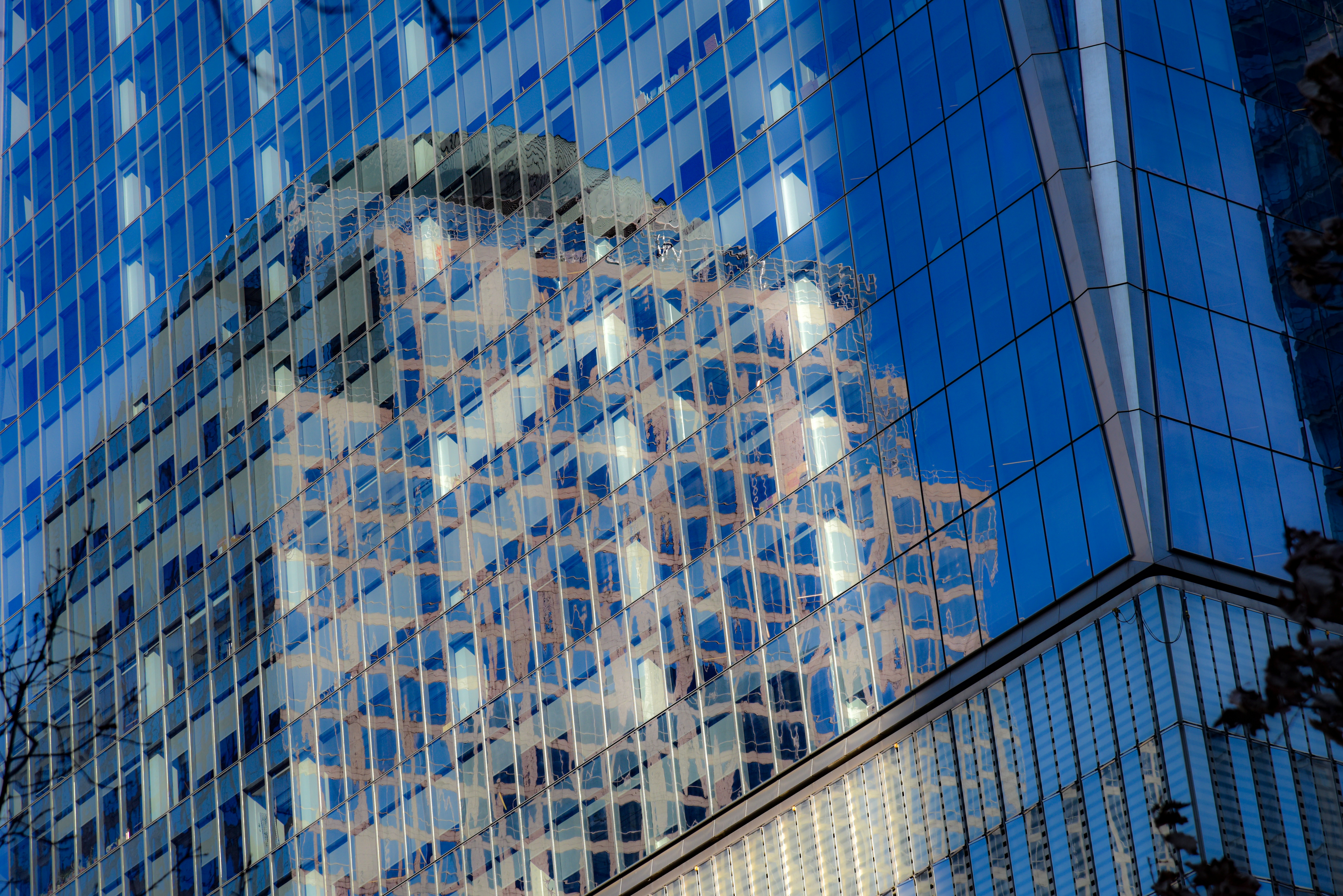Reflection of a modern building in the glass facade of another, showcasing intricate patterns and urban architecture.