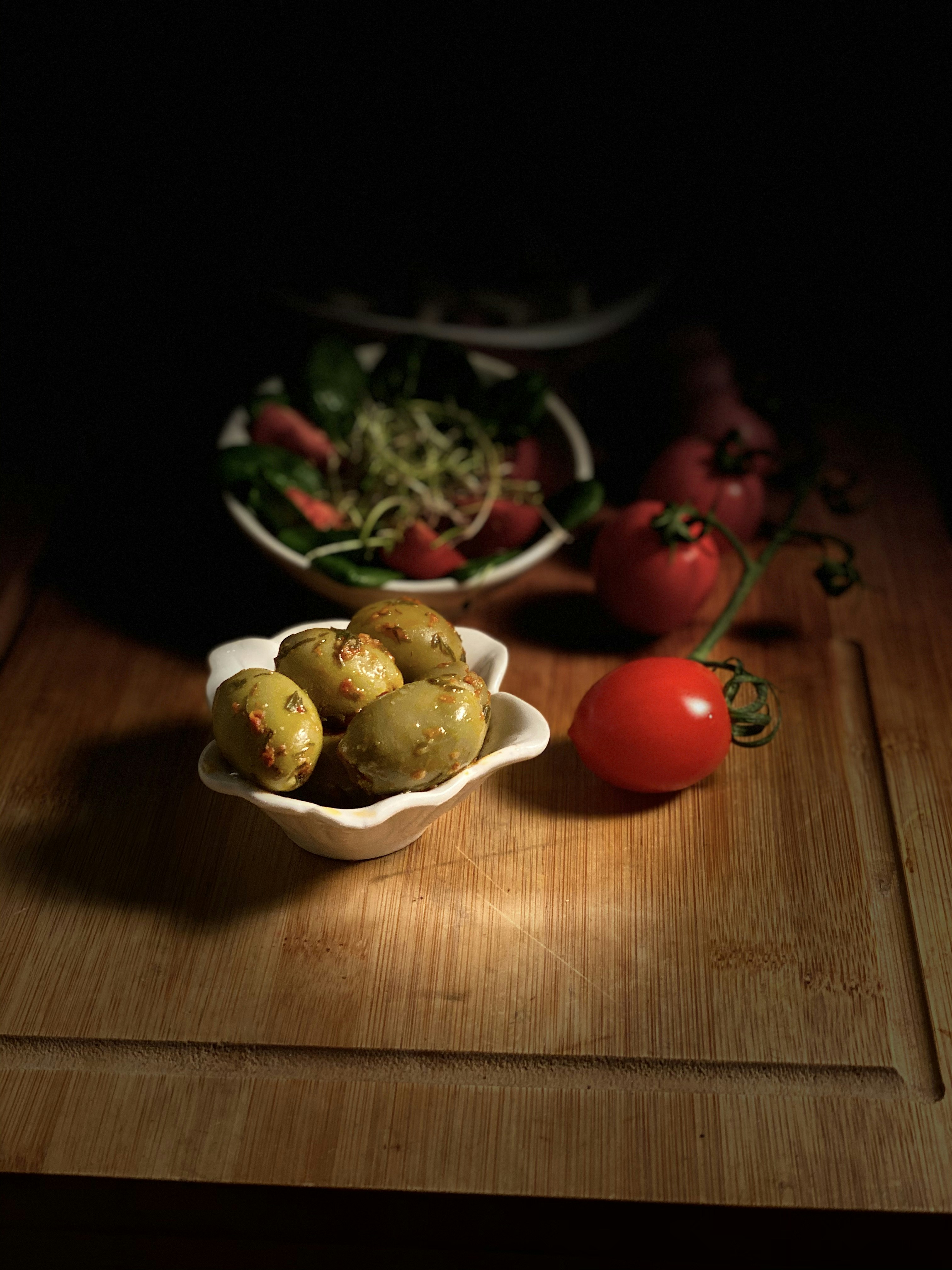 a wooden table topped with bowls of olives and tomatoes