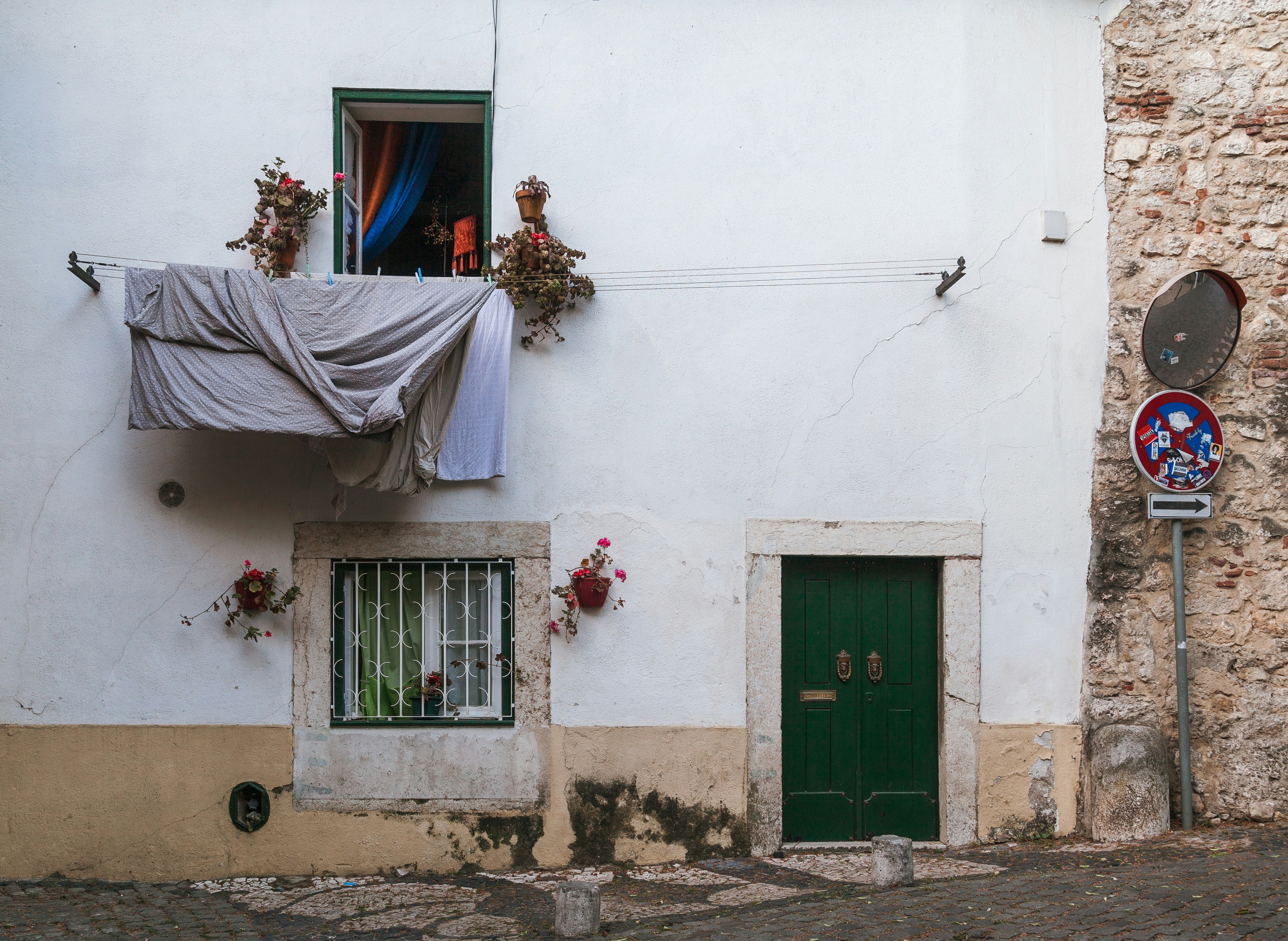 Green Door in a Weathered White Facade Framed by Laundry and Window Boxes